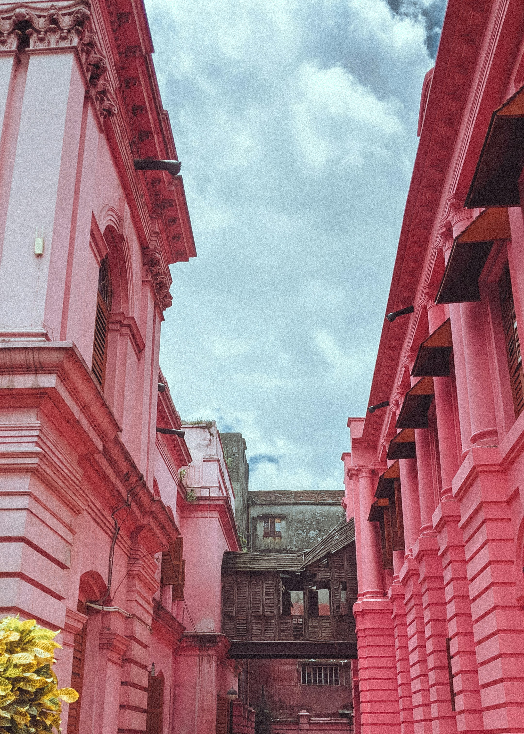 Pink-hued classical architecture framing a cloudy sky.