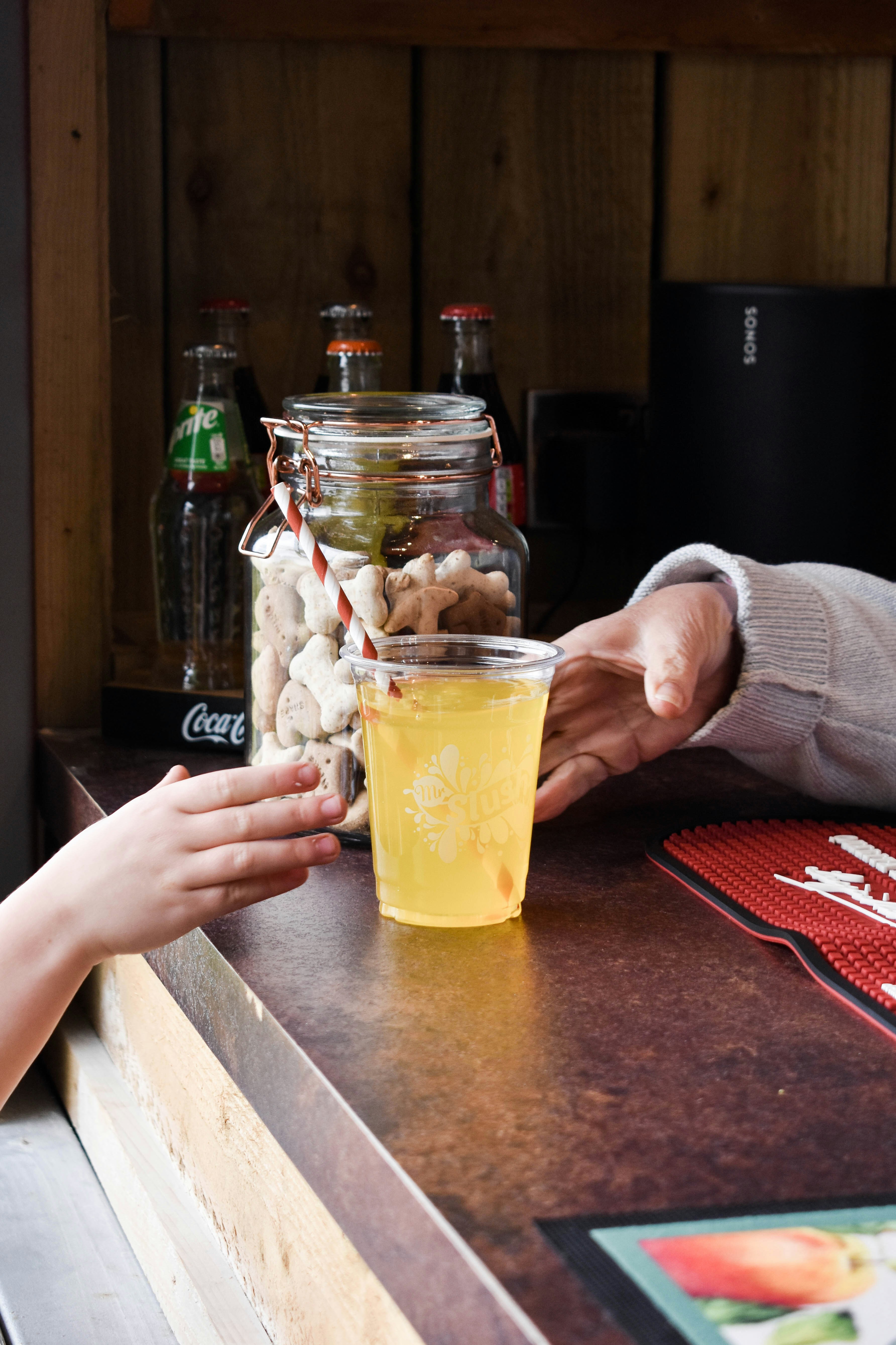 Little kid reaching for cup of juice at cafe | a person holding a glass of beer