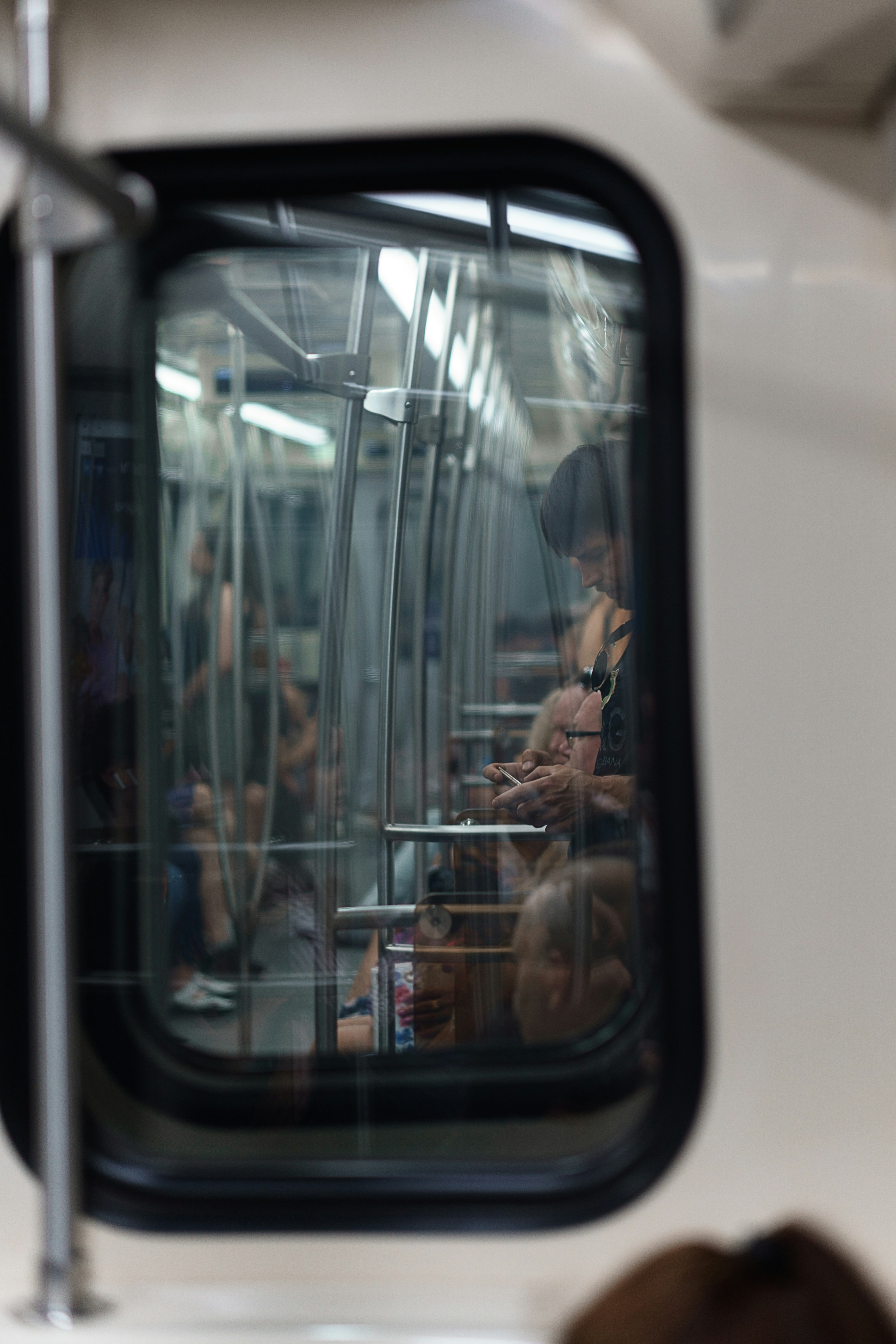 Reflected Moment in a Subway Car: a Quiet Smartphone Portrait Through Glass