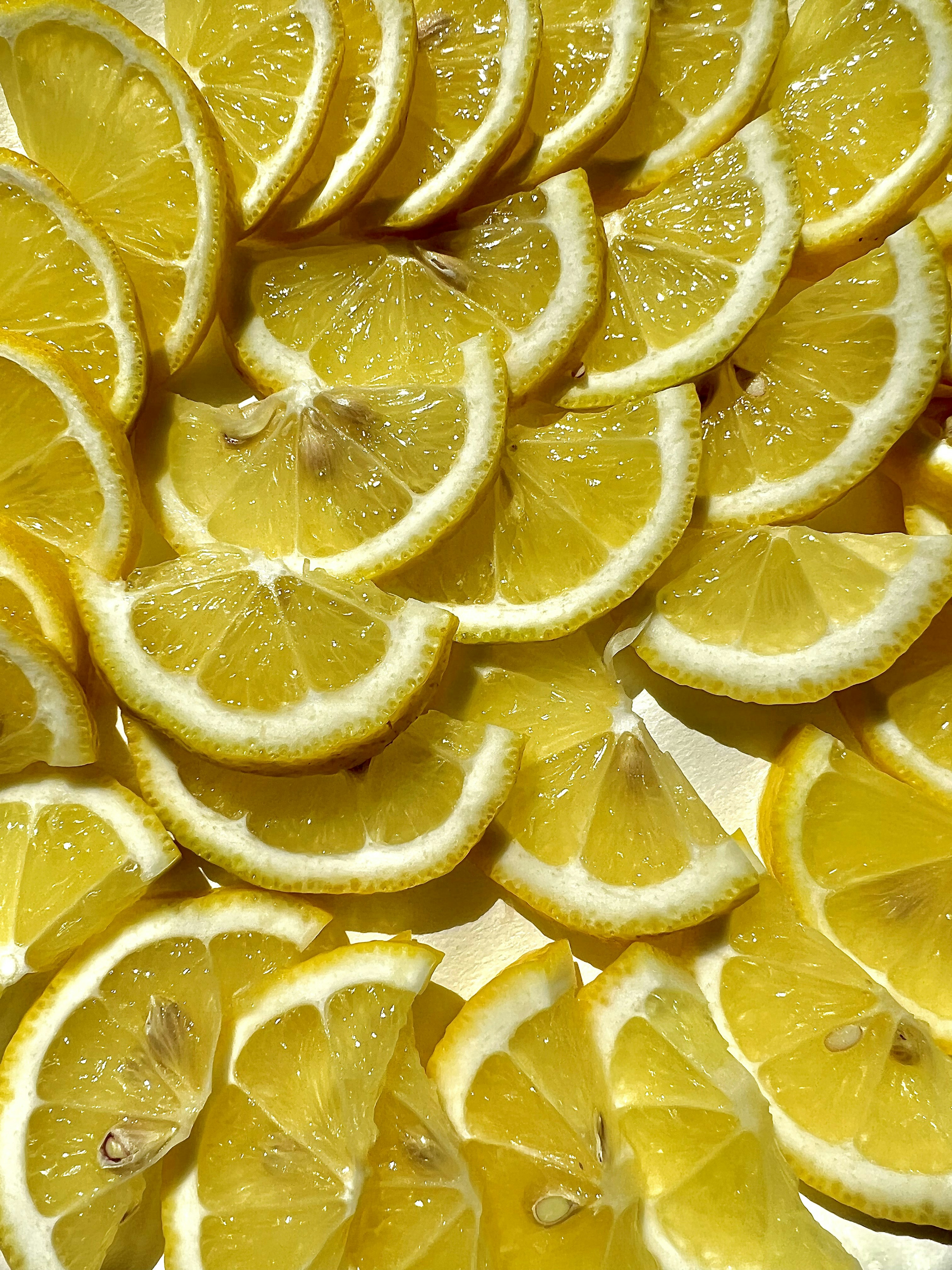 A vibrant arrangement of lemon slices showcasing their bright yellow color and textured surfaces. Ideal for culinary inspiration or refreshing beverage ideas.