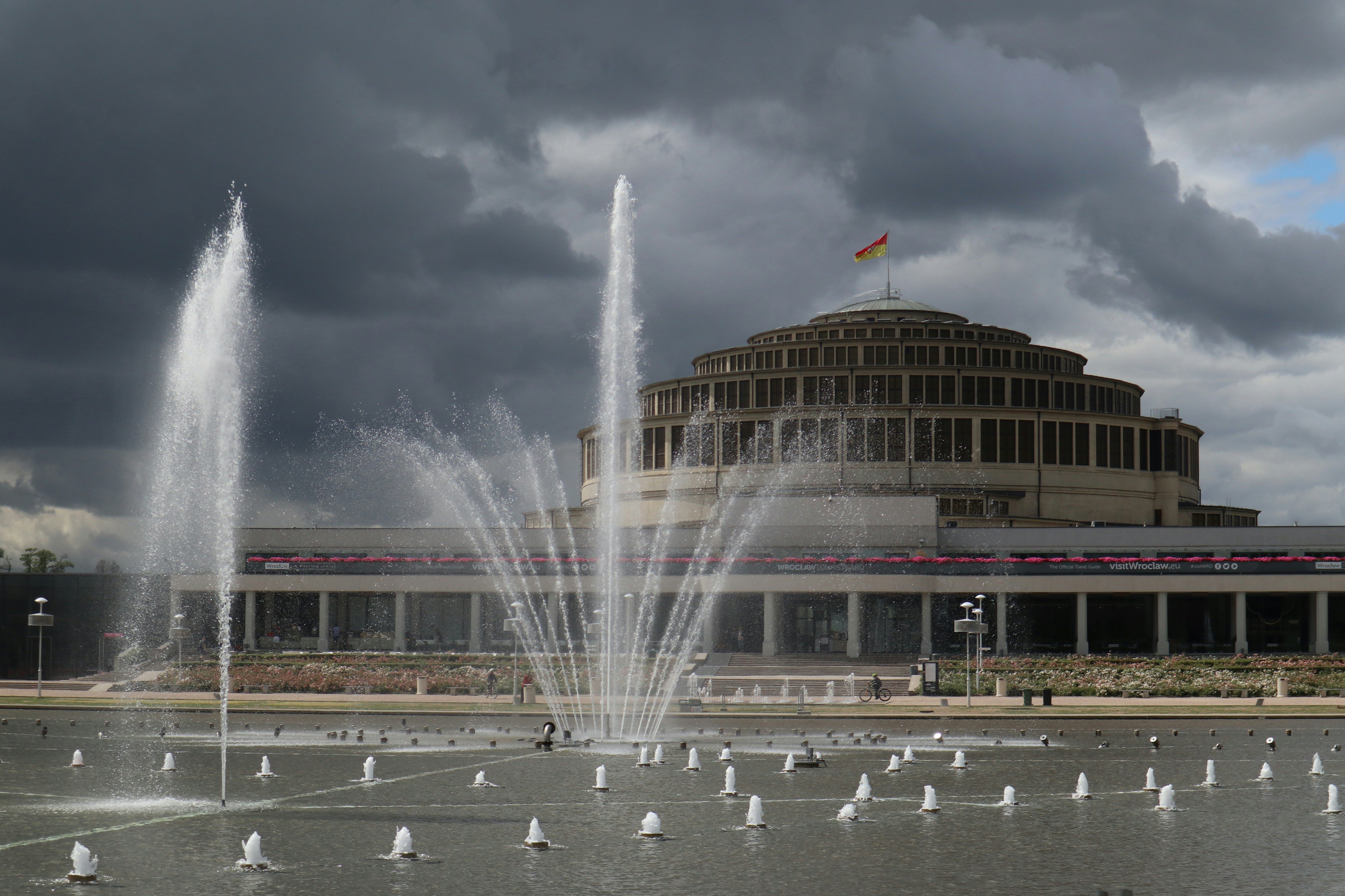 Majestic fountain display in front of a grand historical building under a dramatic sky.