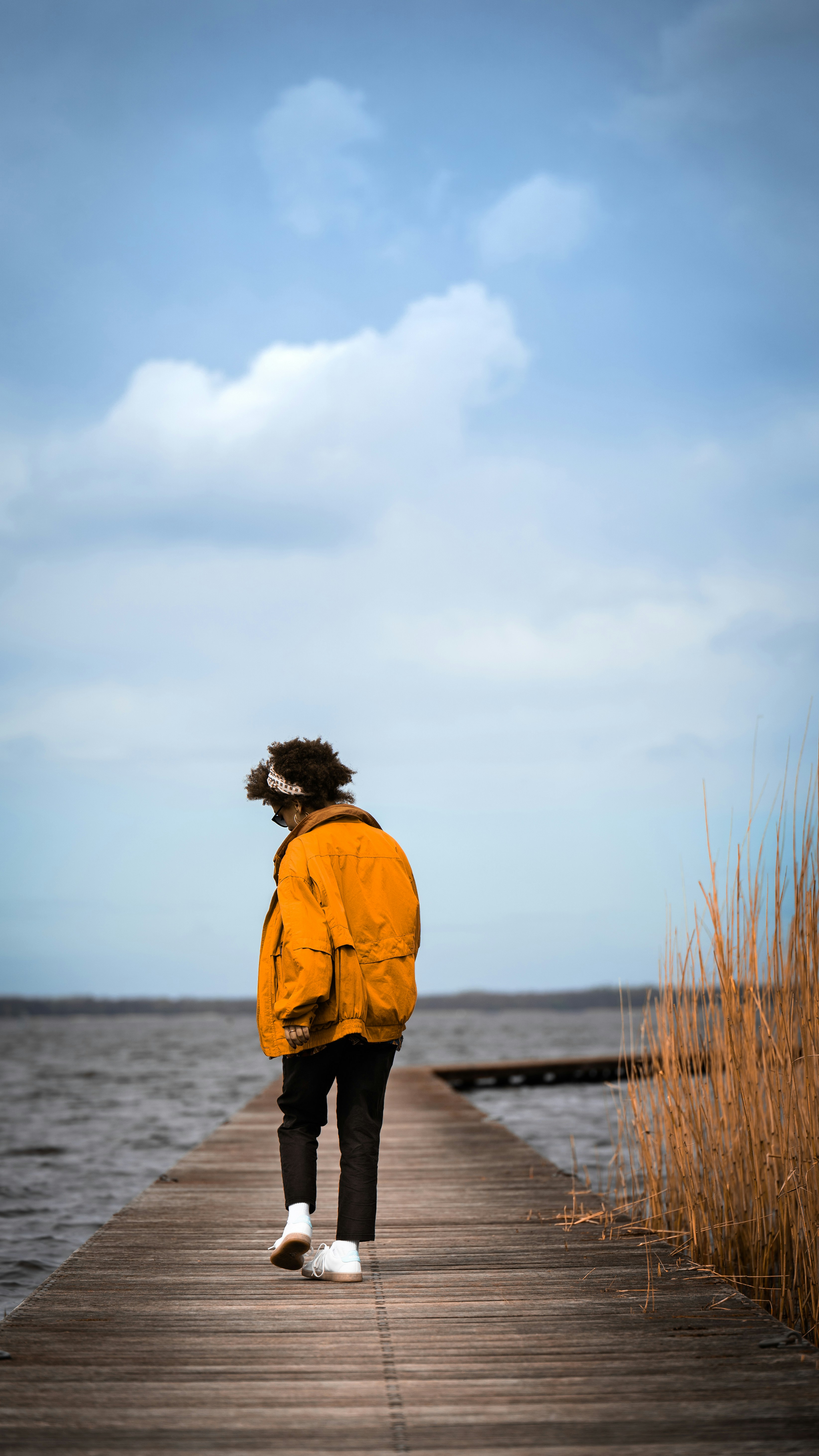 Orange Jacket on a Quiet Pier: Solitude by the Lake