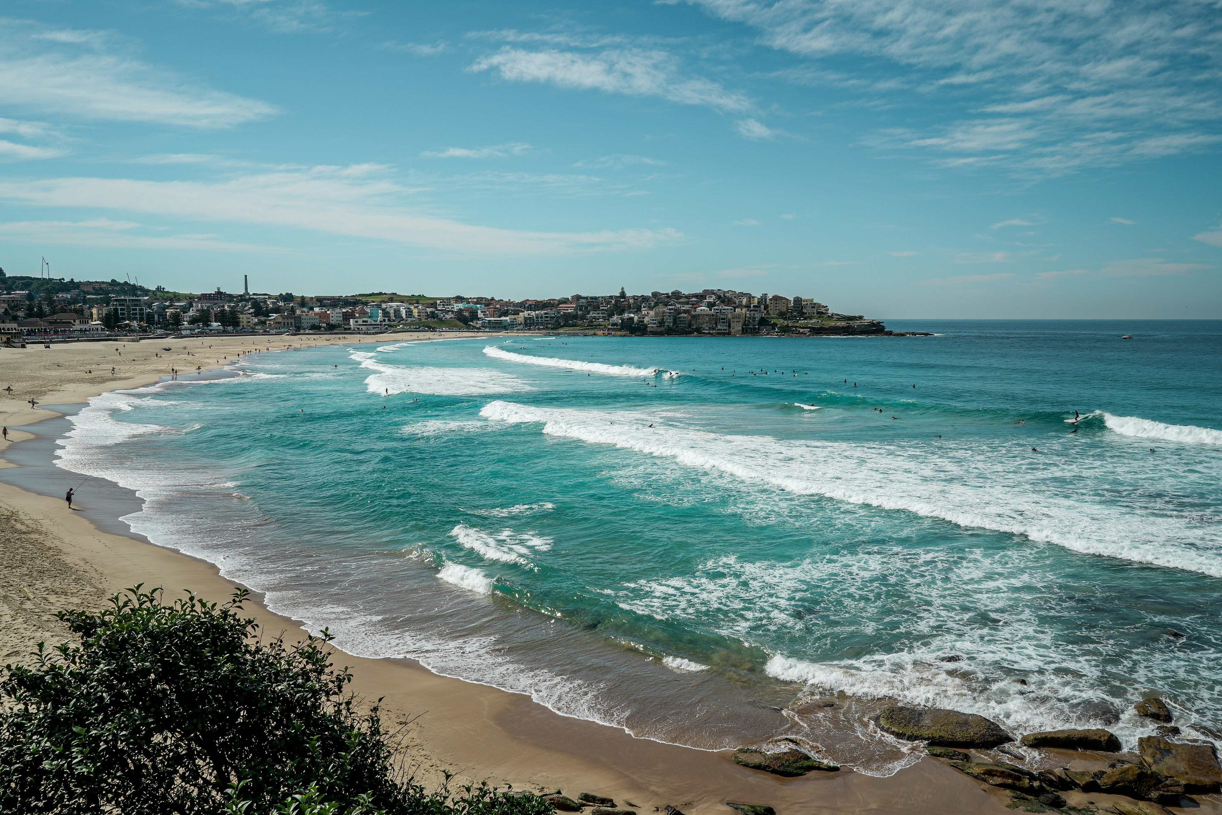 A beach with waves crashing on it with Bondi Beach in the background ...