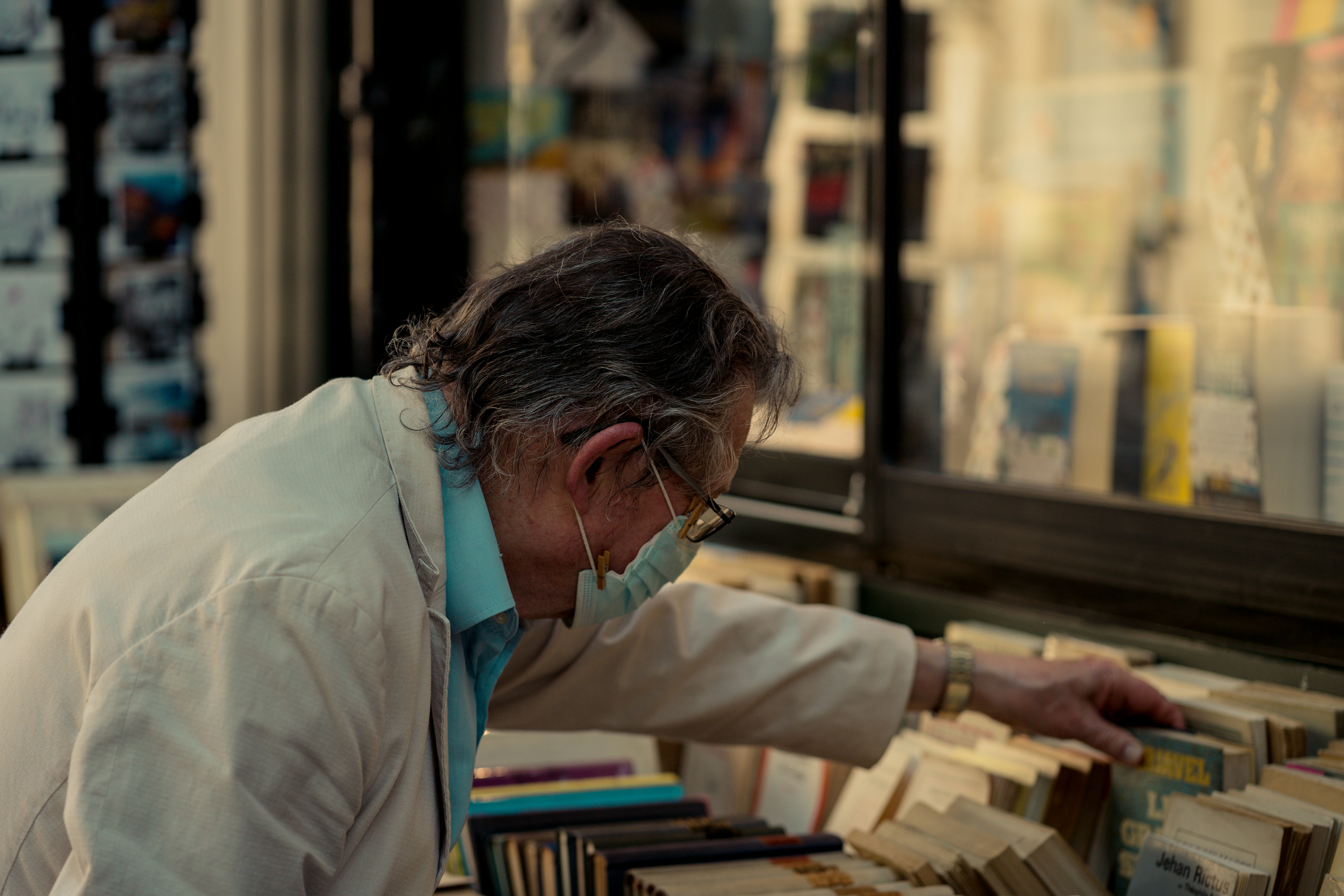 Quiet Pursuit Among the Paperback Aisles: A Masked Reader in a Sunlit Bookshop