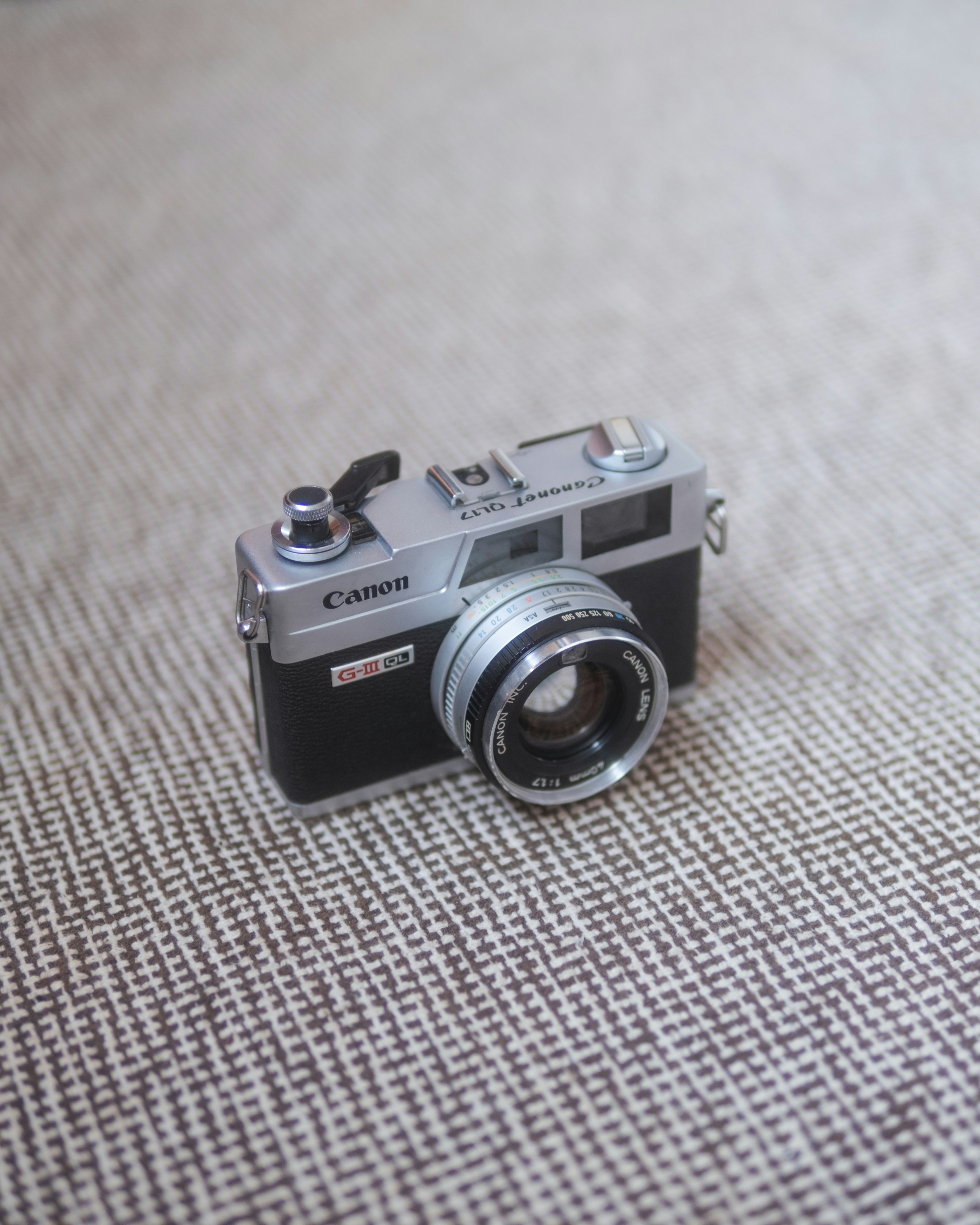Classic Canon camera resting on textured fabric background, showcasing its retro design and intricate details.