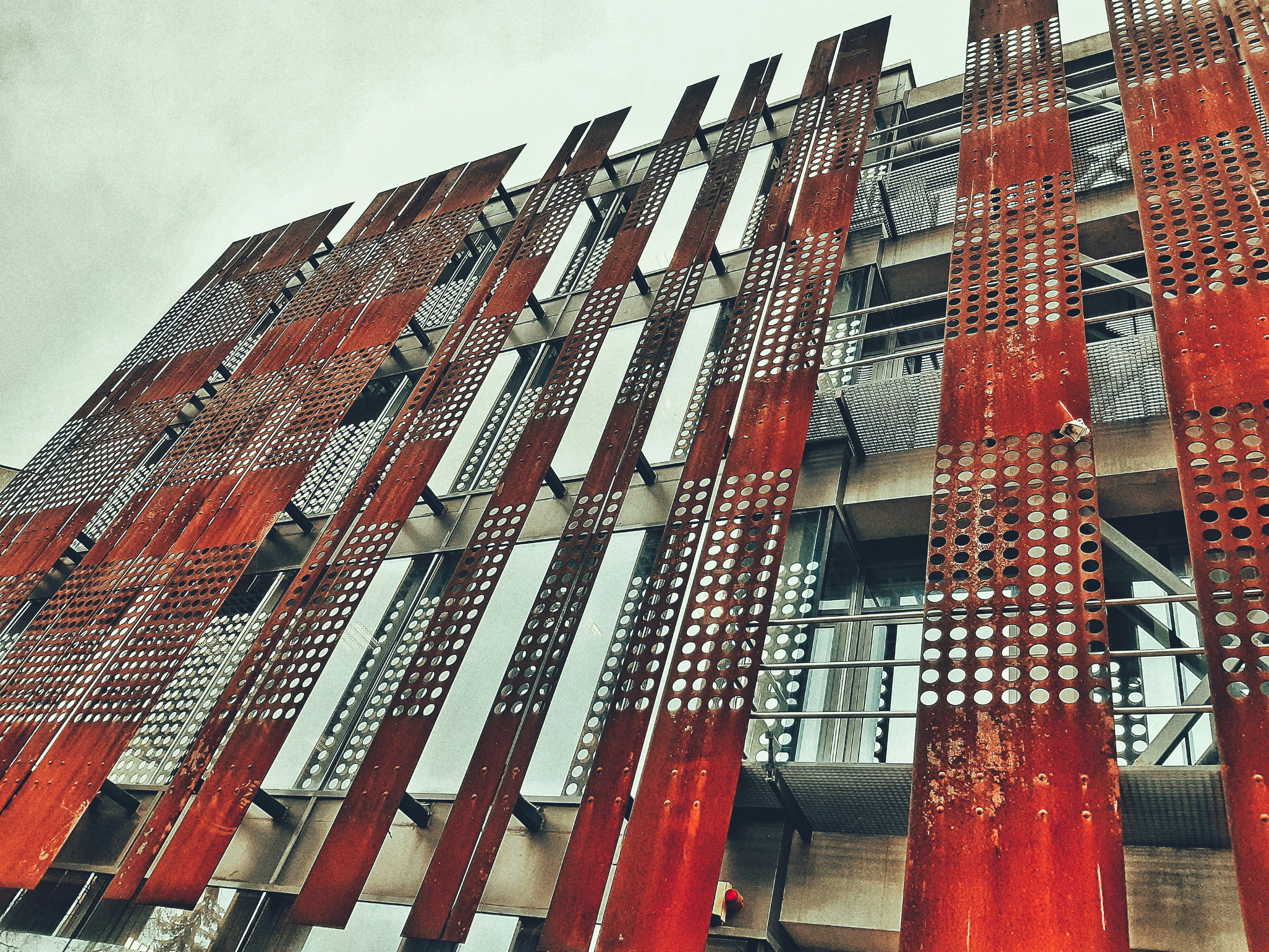 Contemporary building facade with striking red pillars and metallic elements.