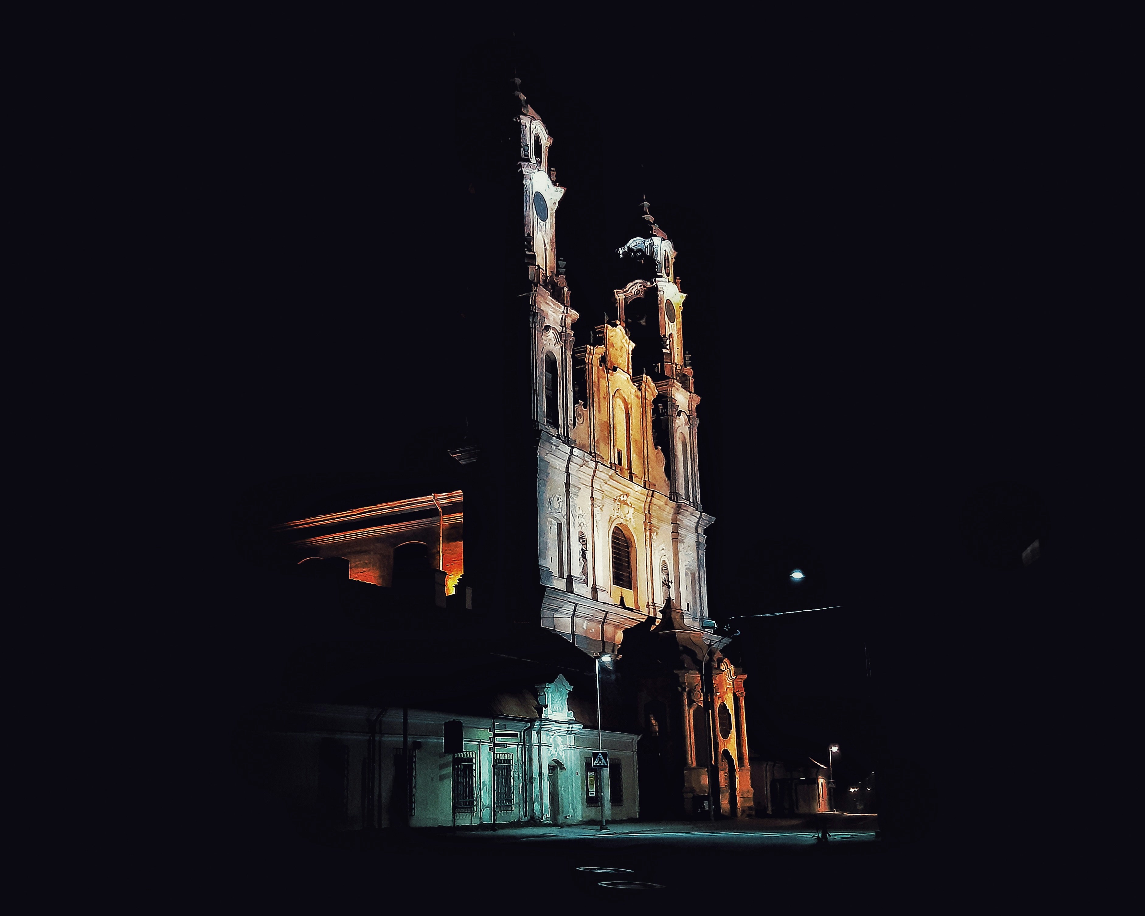 Historic cathedral glowing under night sky with intricate architectural details highlighted by artificial lights.