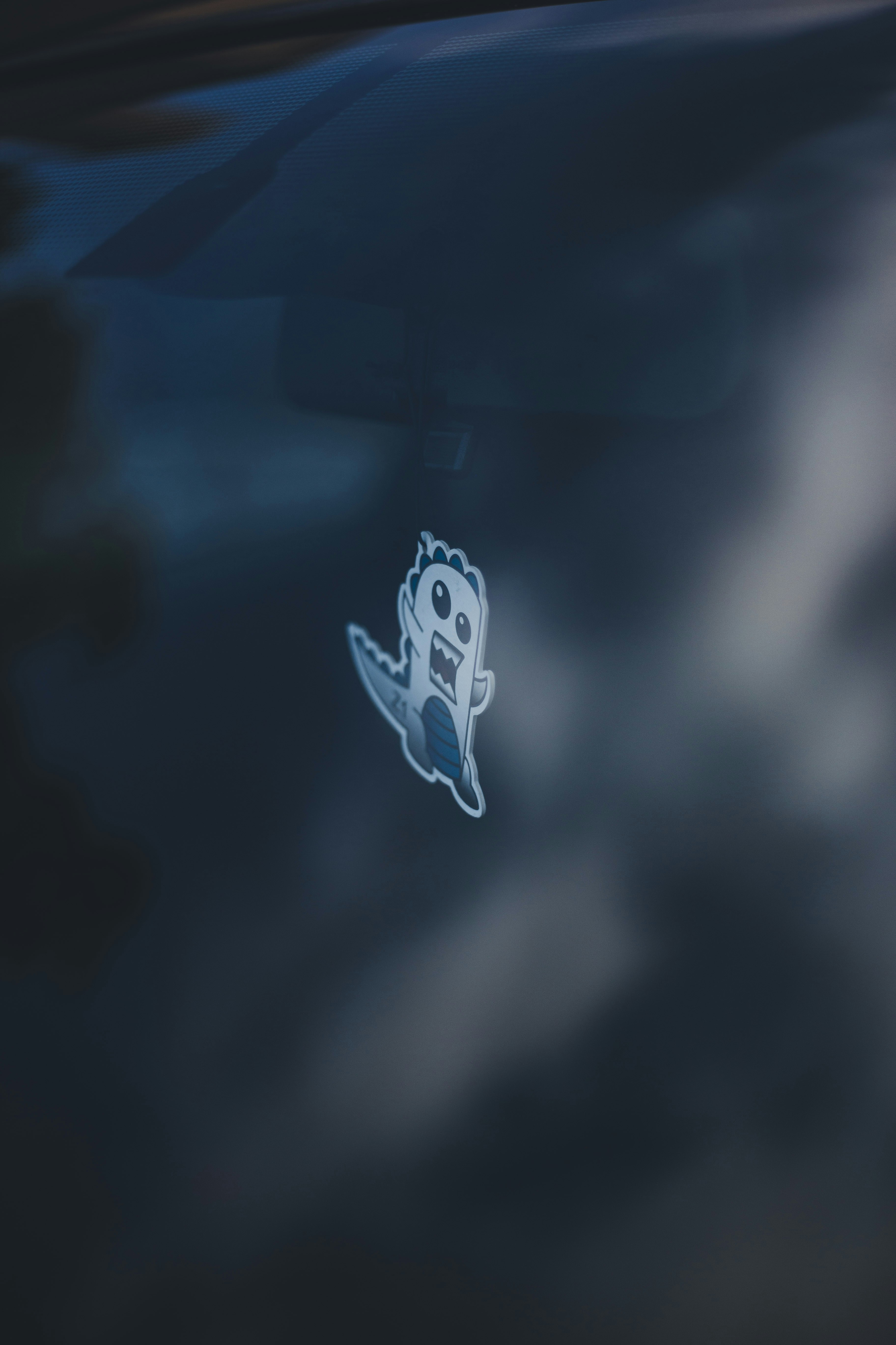 A playful cartoon dinosaur sticker adorning the interior of a vehicle, capturing a lighthearted moment amidst a blurred background.