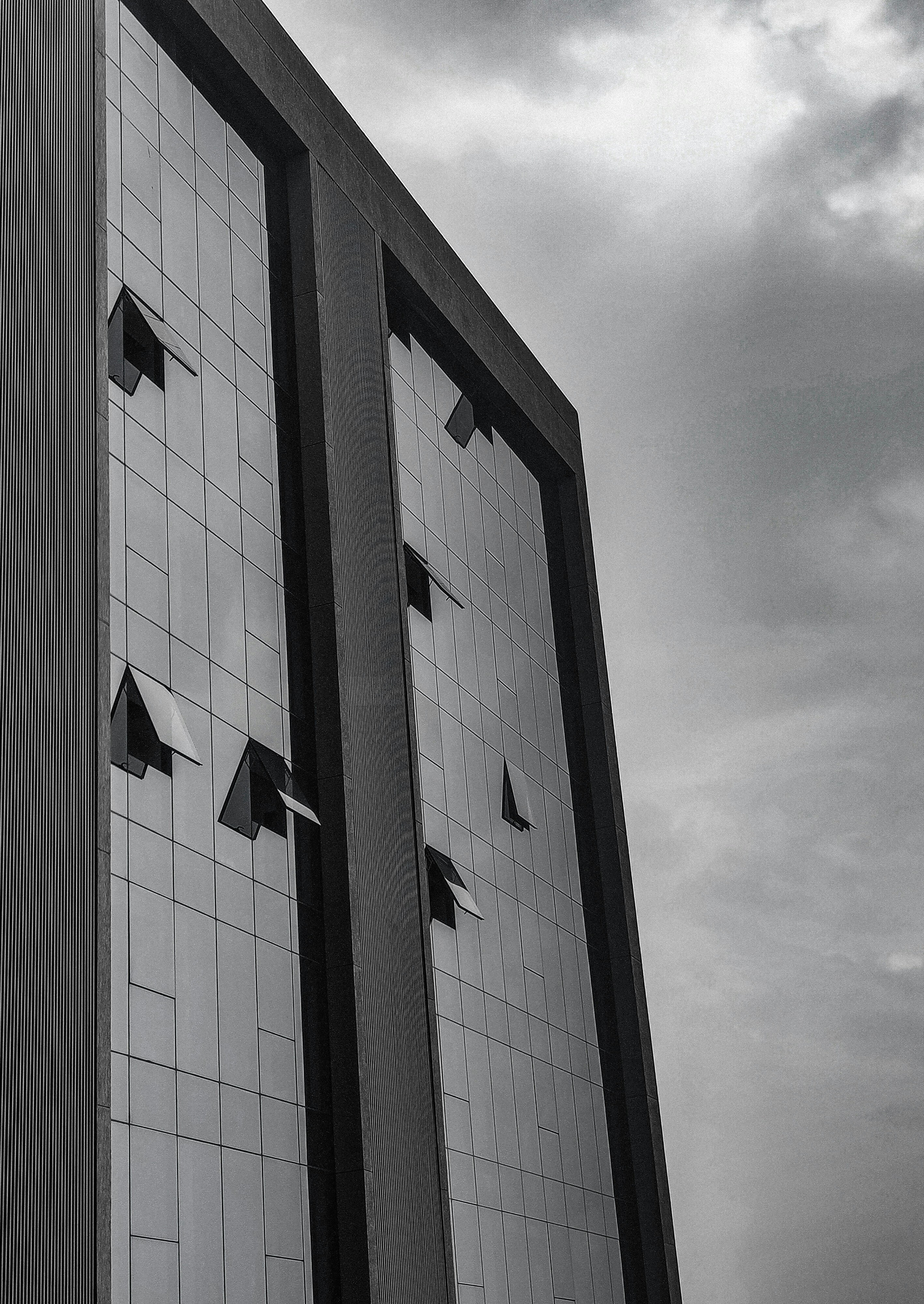 Geometric patterns and reflective surfaces of a contemporary building juxtaposed against a moody sky.