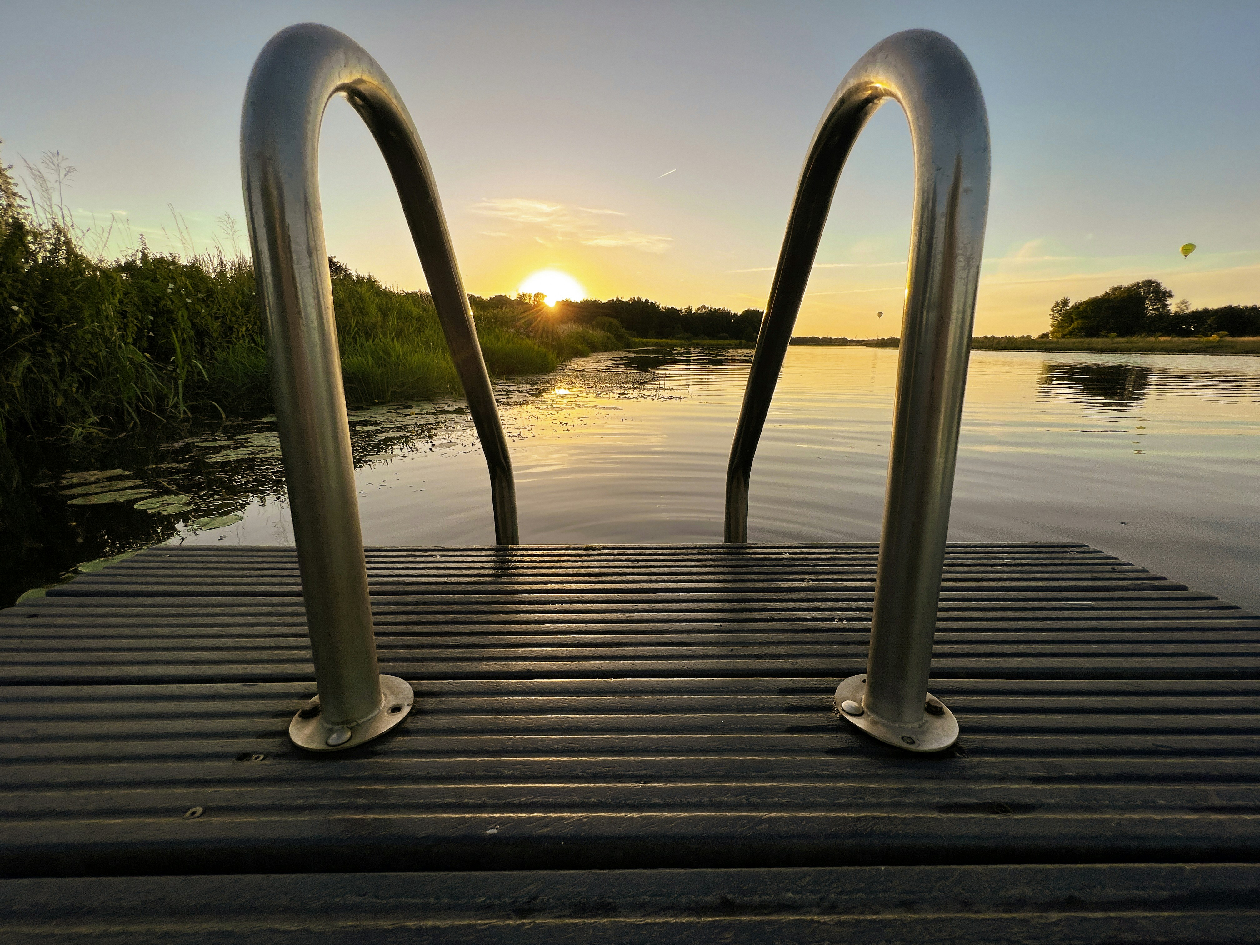 Twin Rails at Golden Hour: A Quiet Lakeside Dock Reaches for the Sun