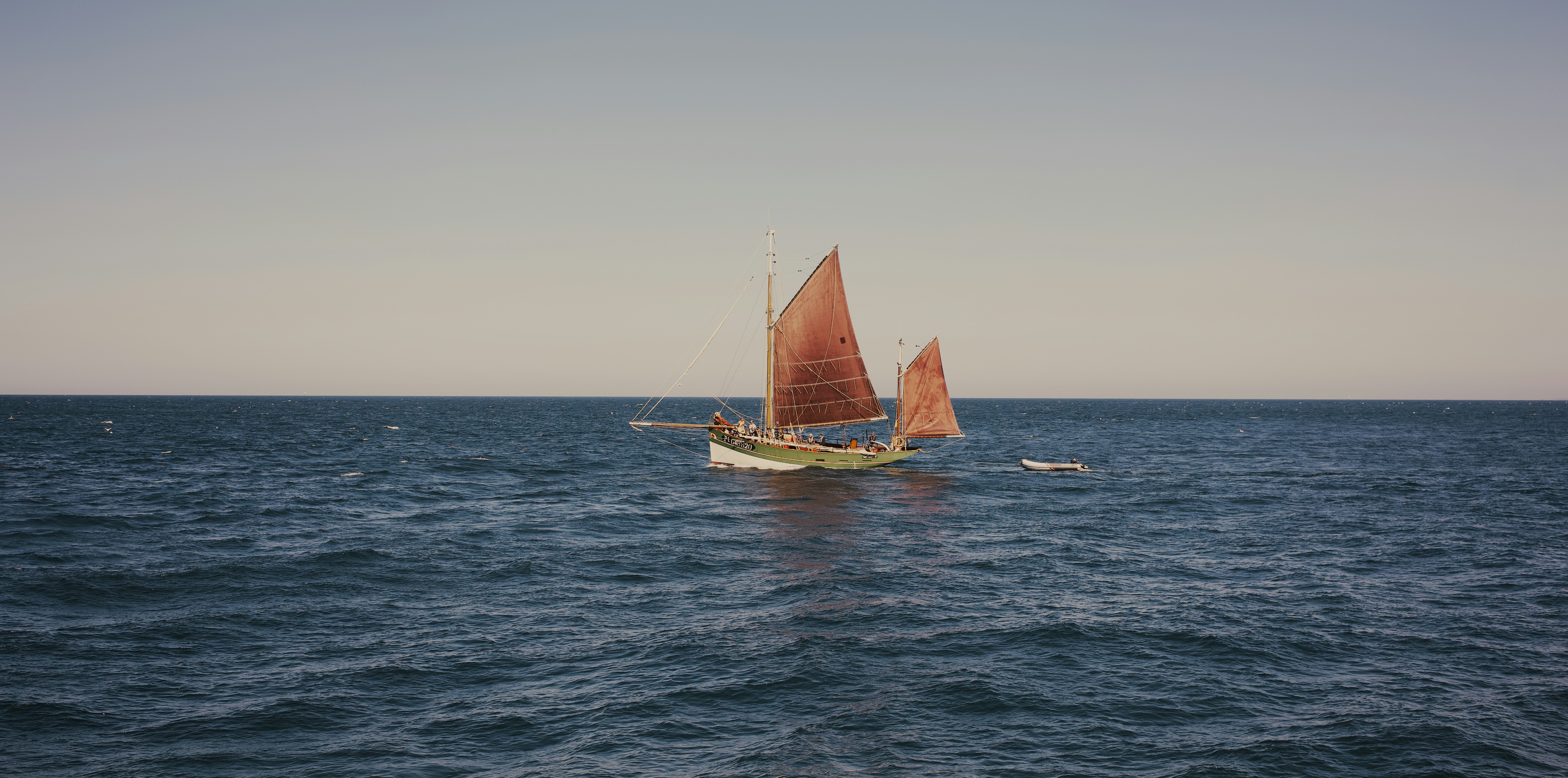 Red-sailed Schooner Slicing the Quiet Atlantic