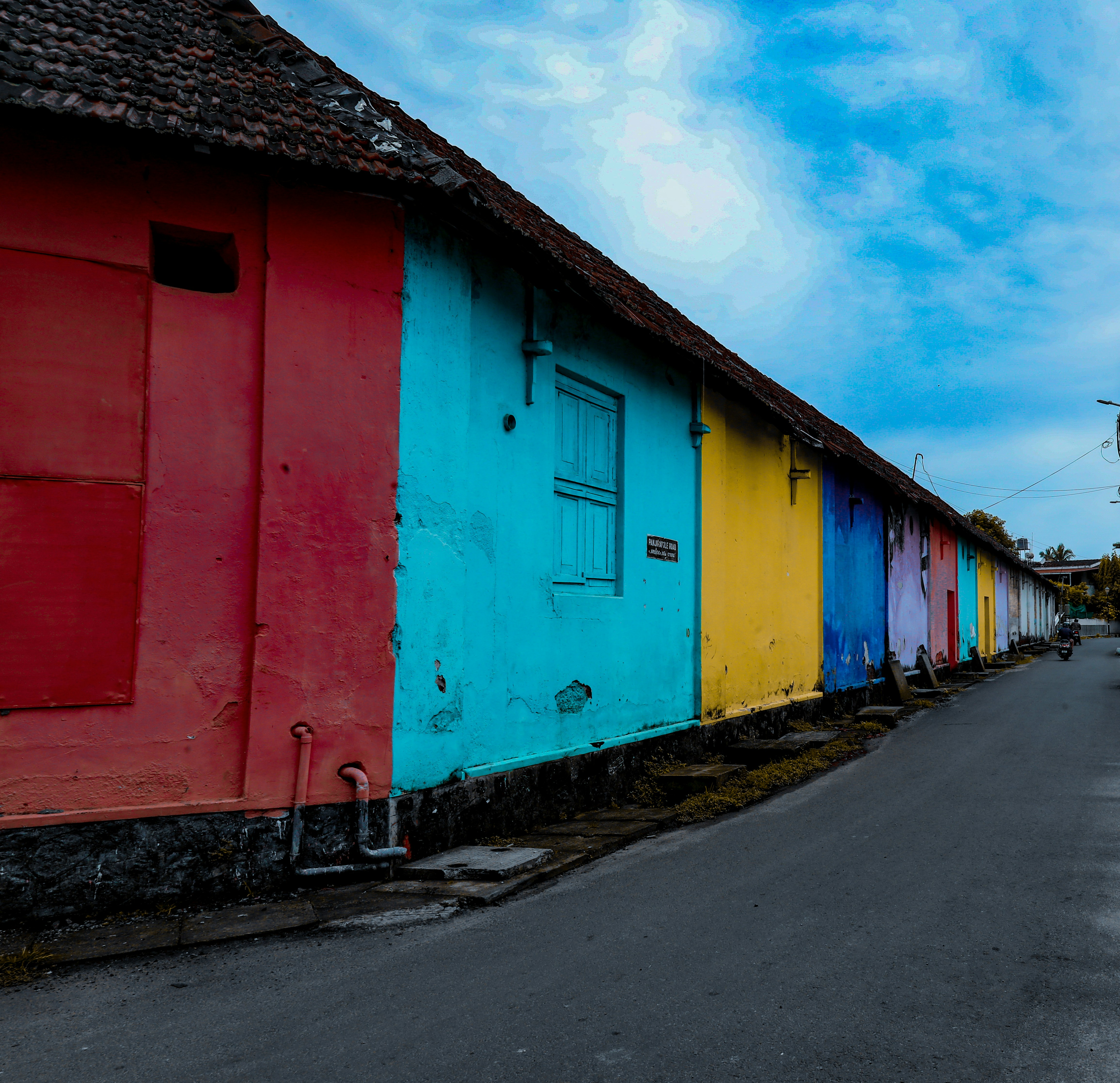 Row of vividly painted buildings lining a quiet street under a clear sky.