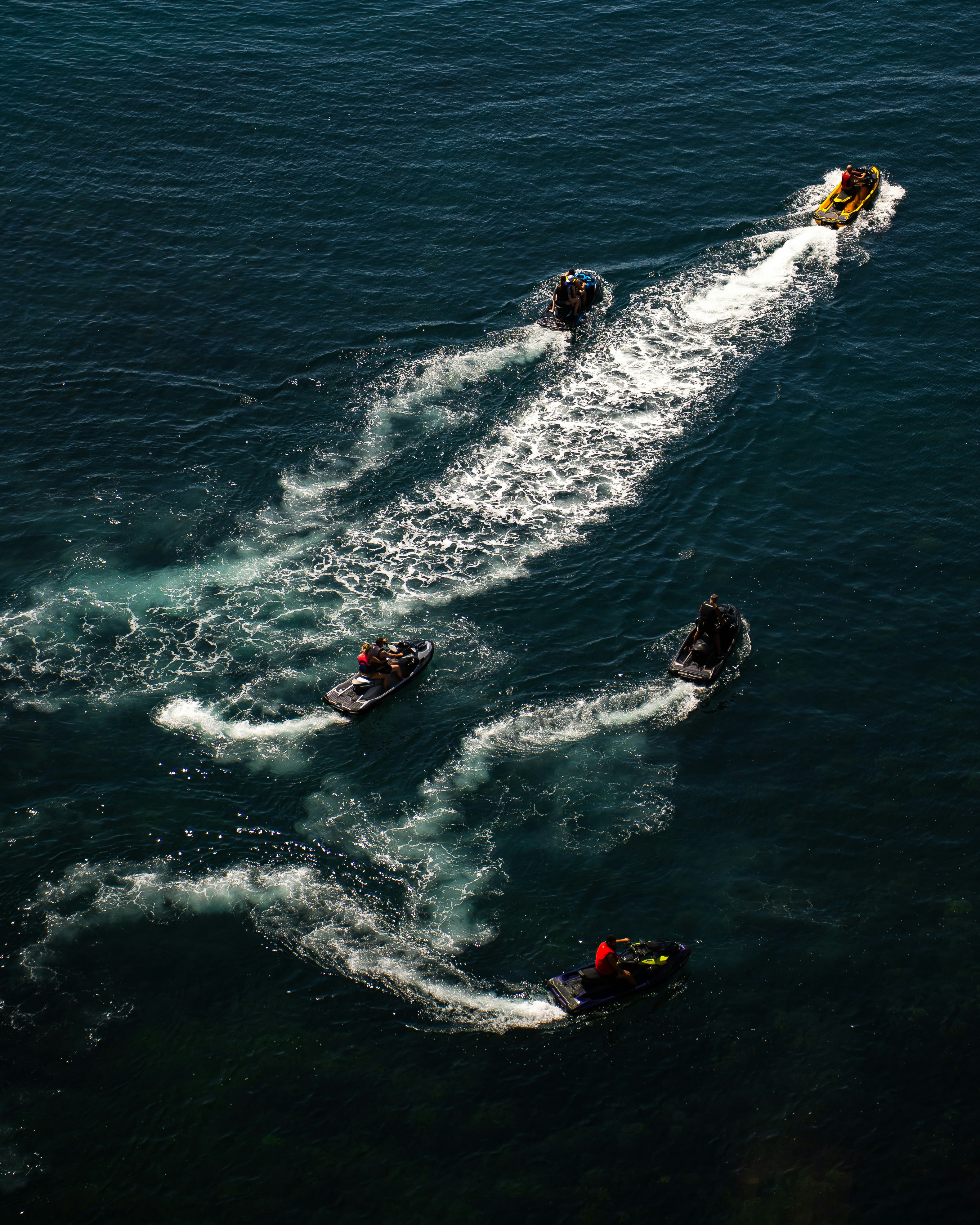 Five Watercraft Leave a Foamy Trail Across Dusk-Blue Sea