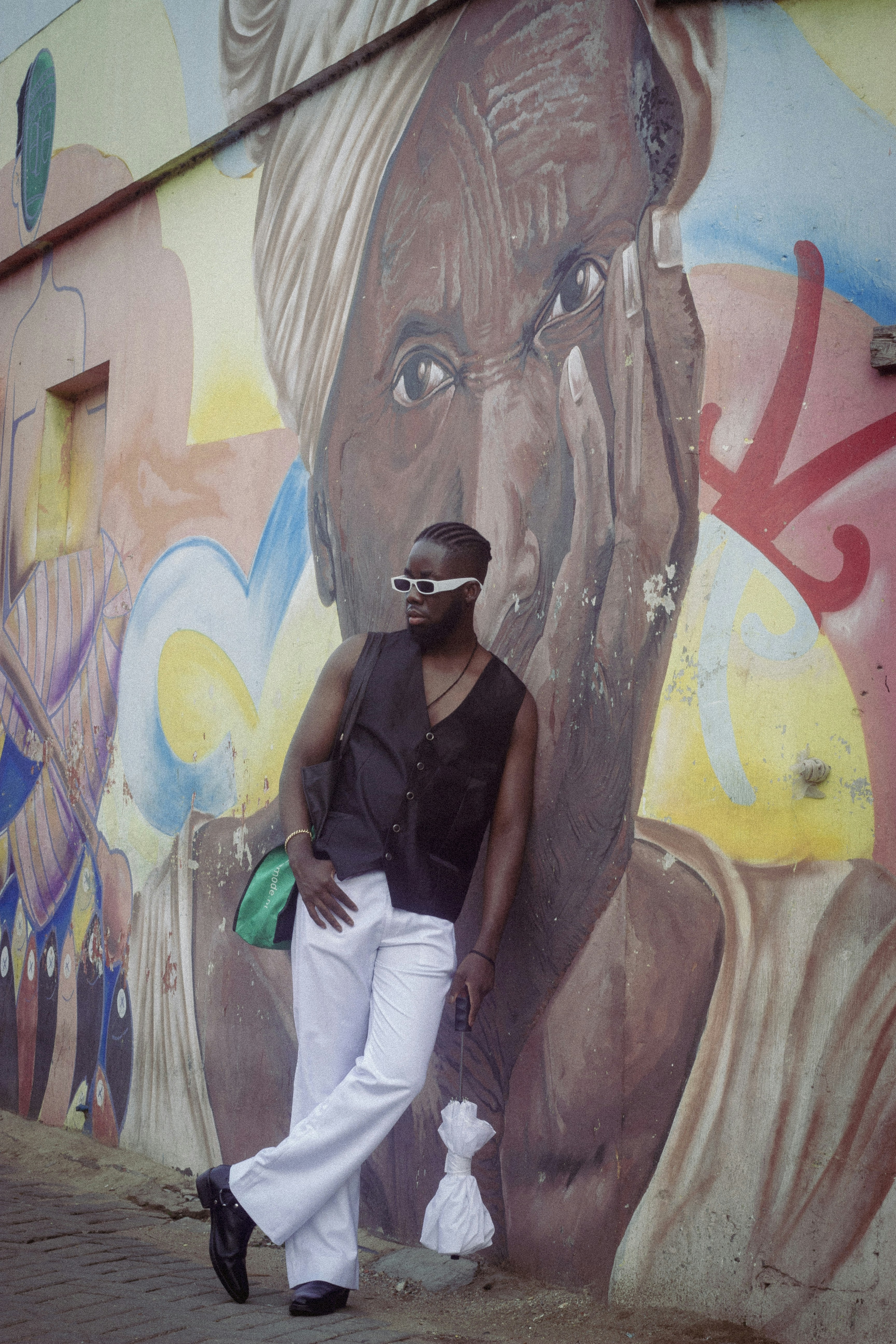 Shadow and Color: A Dapper Figure Leans Against a Graffiti Portrait