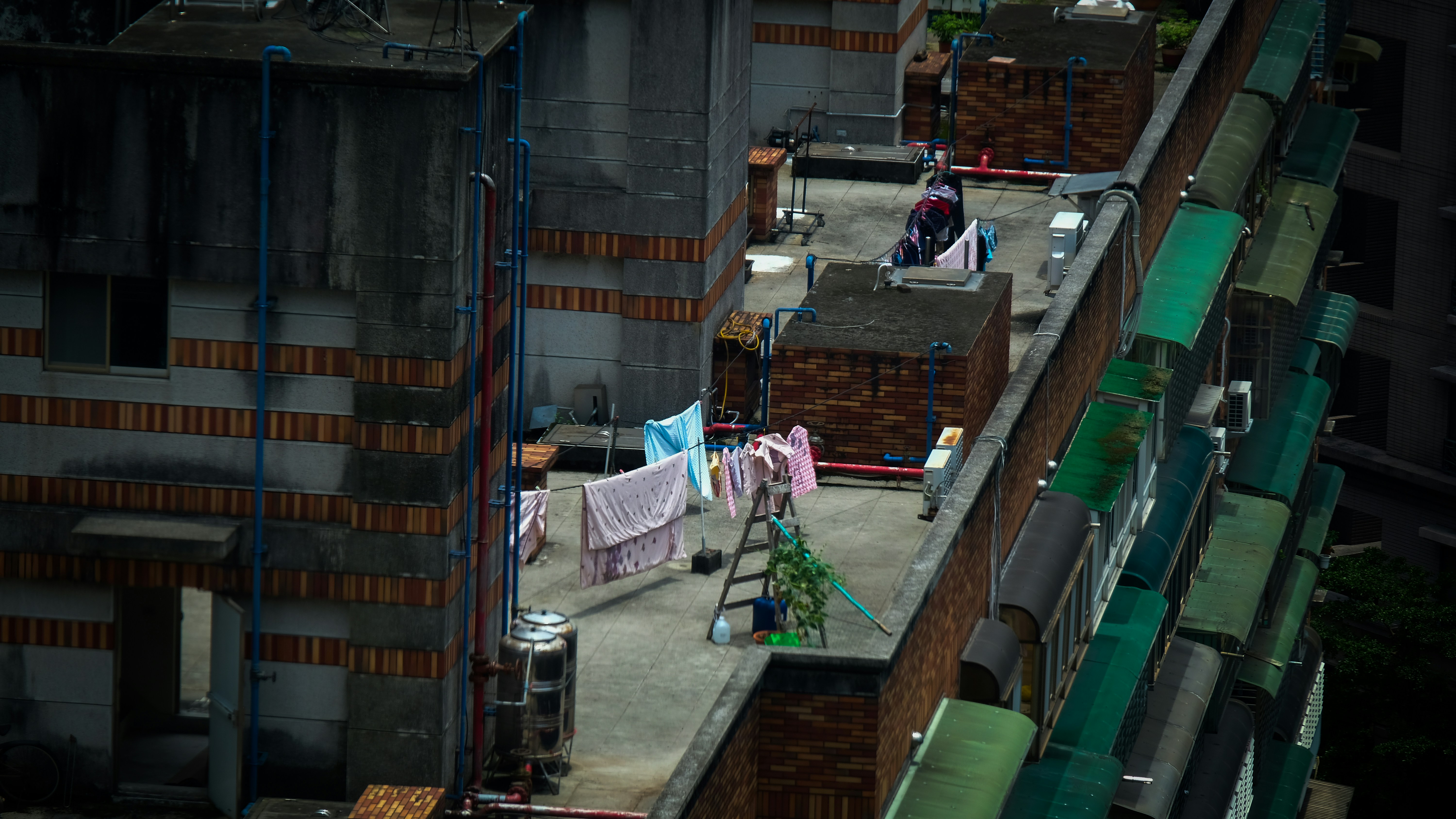 Laundry hanging on rooftop terraces amidst urban architecture, showcasing daily life in a city environment.