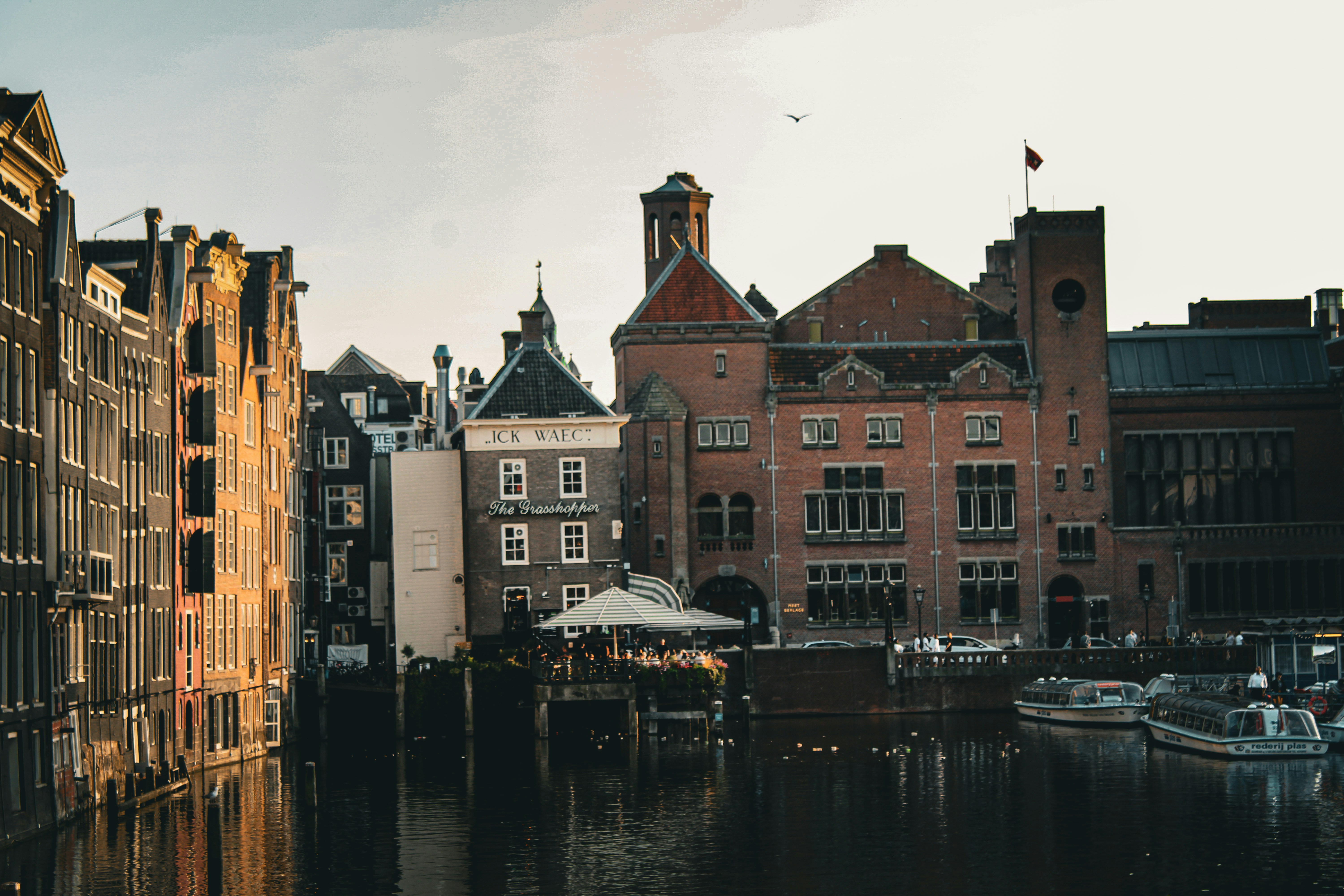 Historic buildings lining a tranquil canal with boats docked, capturing the essence of Amsterdam's architectural charm.