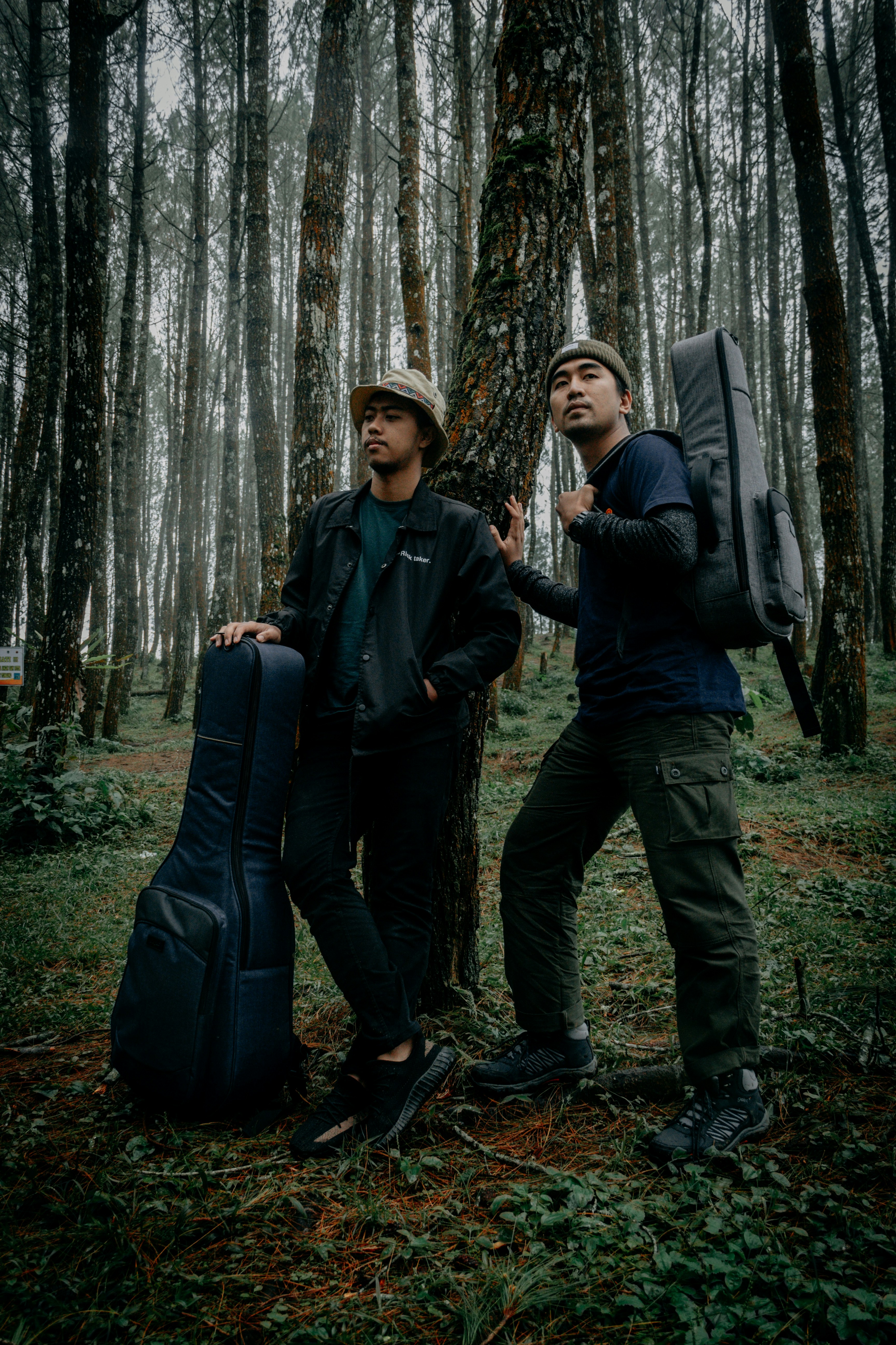 Echoes Through Pine and Pitch: Two Musicians Trek with Guitar Cases in a Mossy Forest