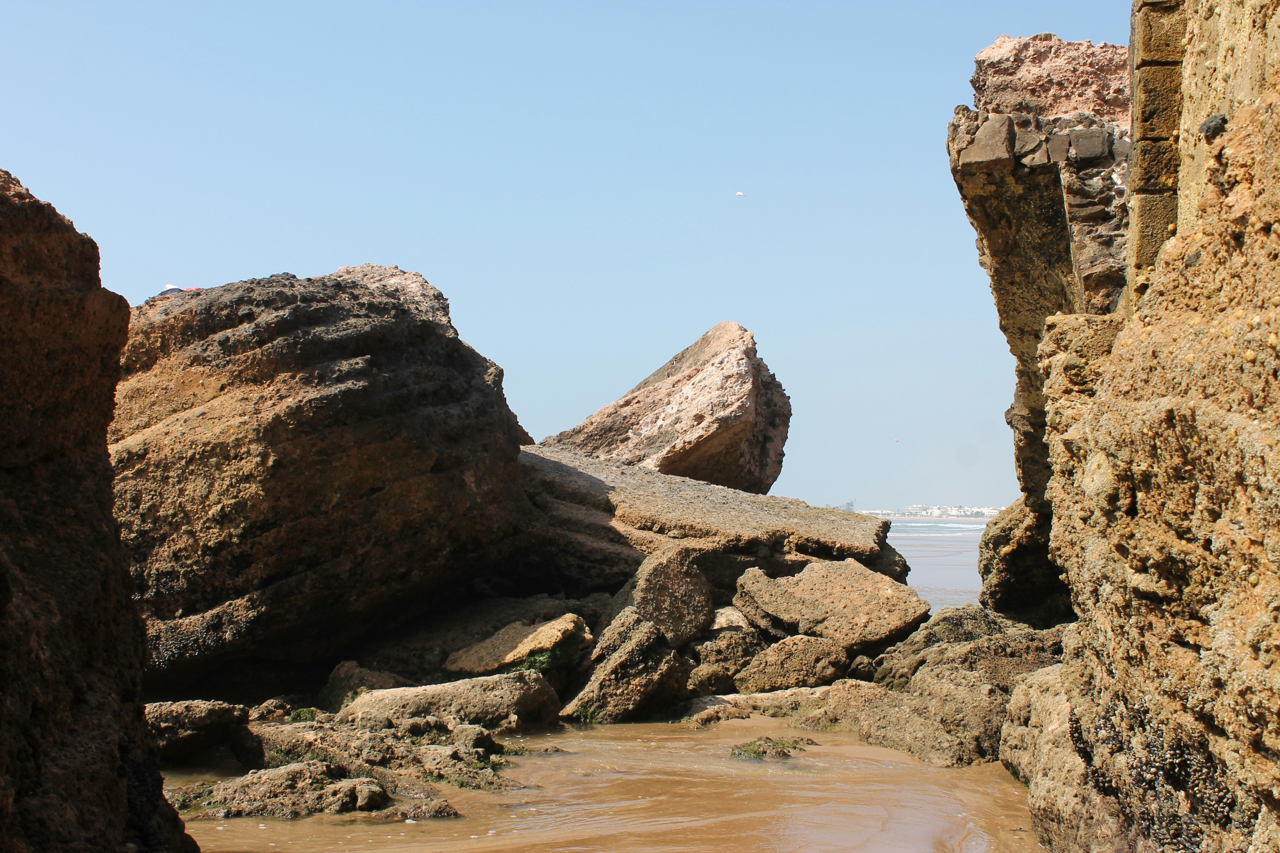 Sunlit Gap Between Time-Worn Cliffs Framing a Distant Sea Rock