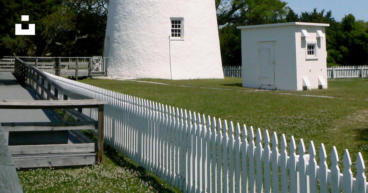 배경에 Ocracoke가 있는 흰색 울타리가 있는 흰색 등대 사진 Unsplash의 무료 건물 이미지