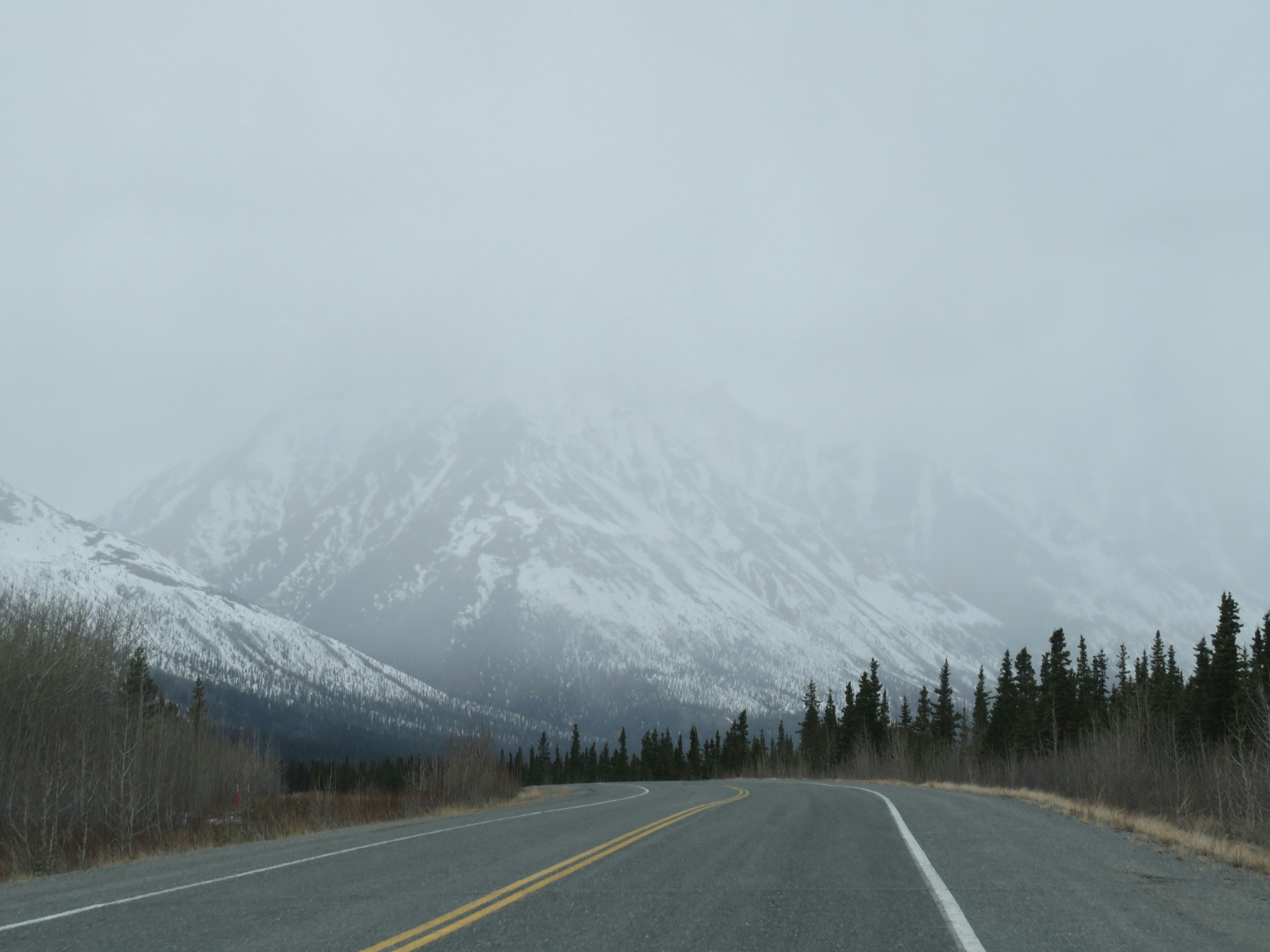 Vanishing Mile: Snow-Blanketed Highway Beneath a Shrouded Peak