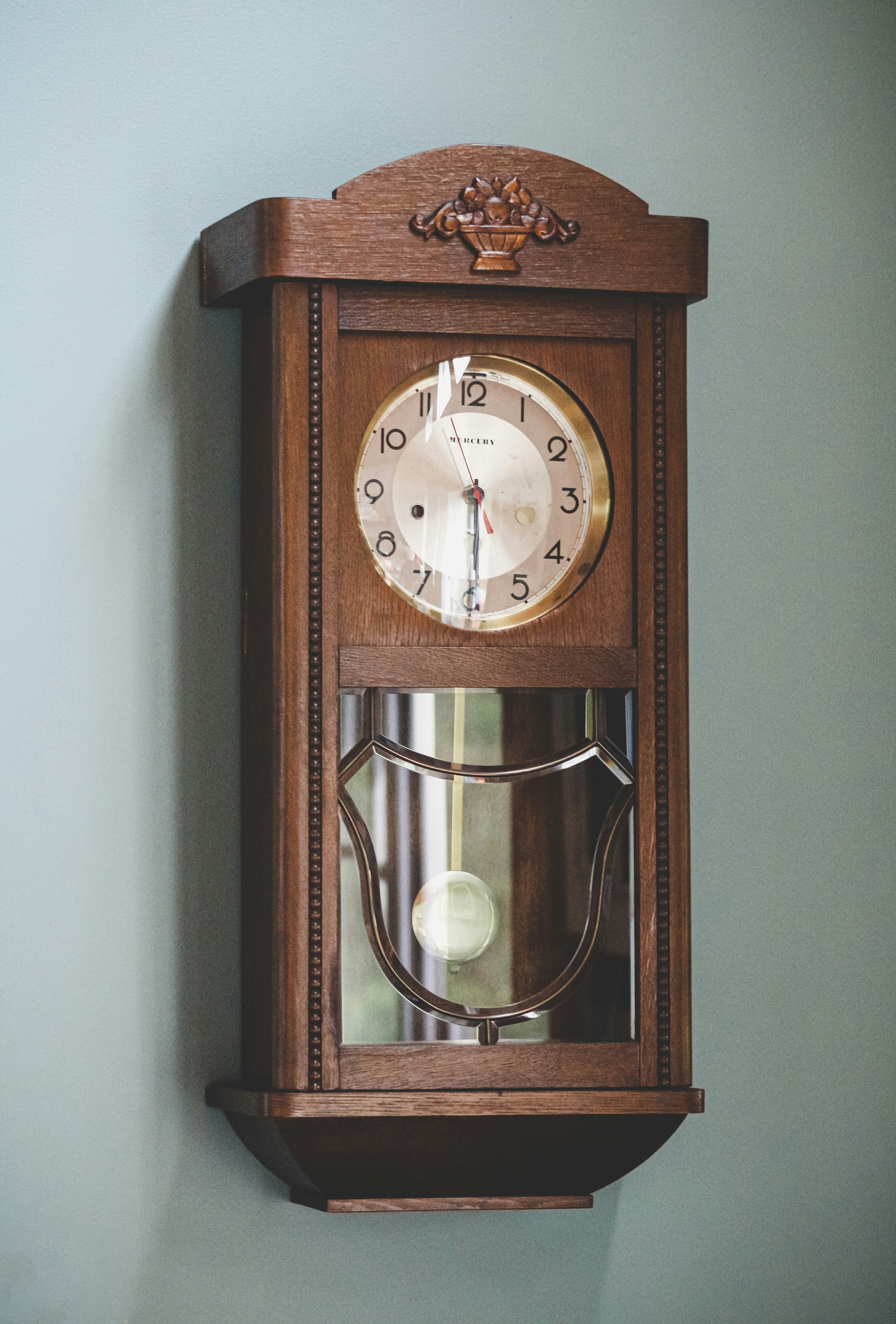 Timeless Wood, Quiet Pendulum: Vintage Wall Clock Adorning a Pale Blue Wall