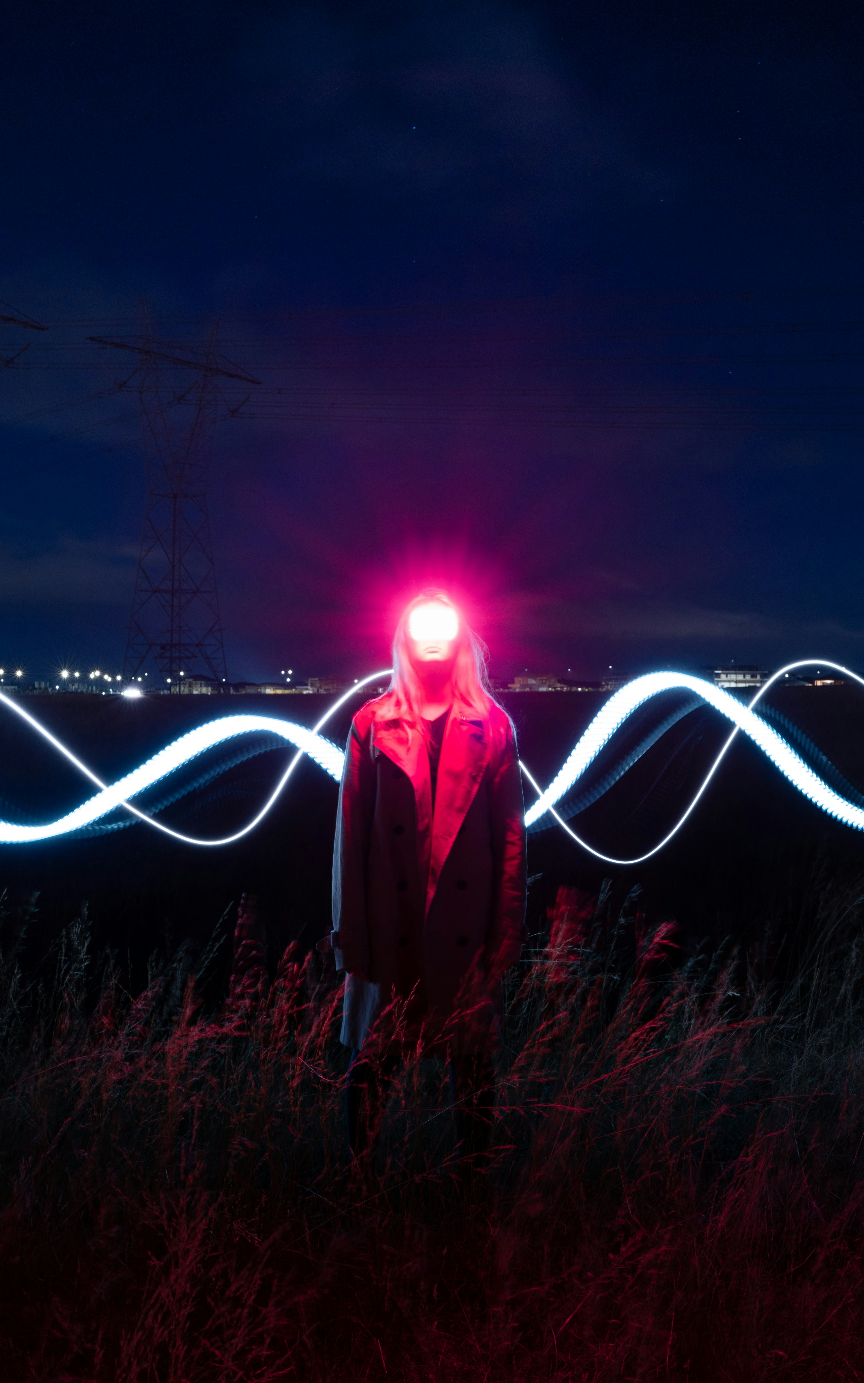 A person standing in a field with a bright light behind them photo ...