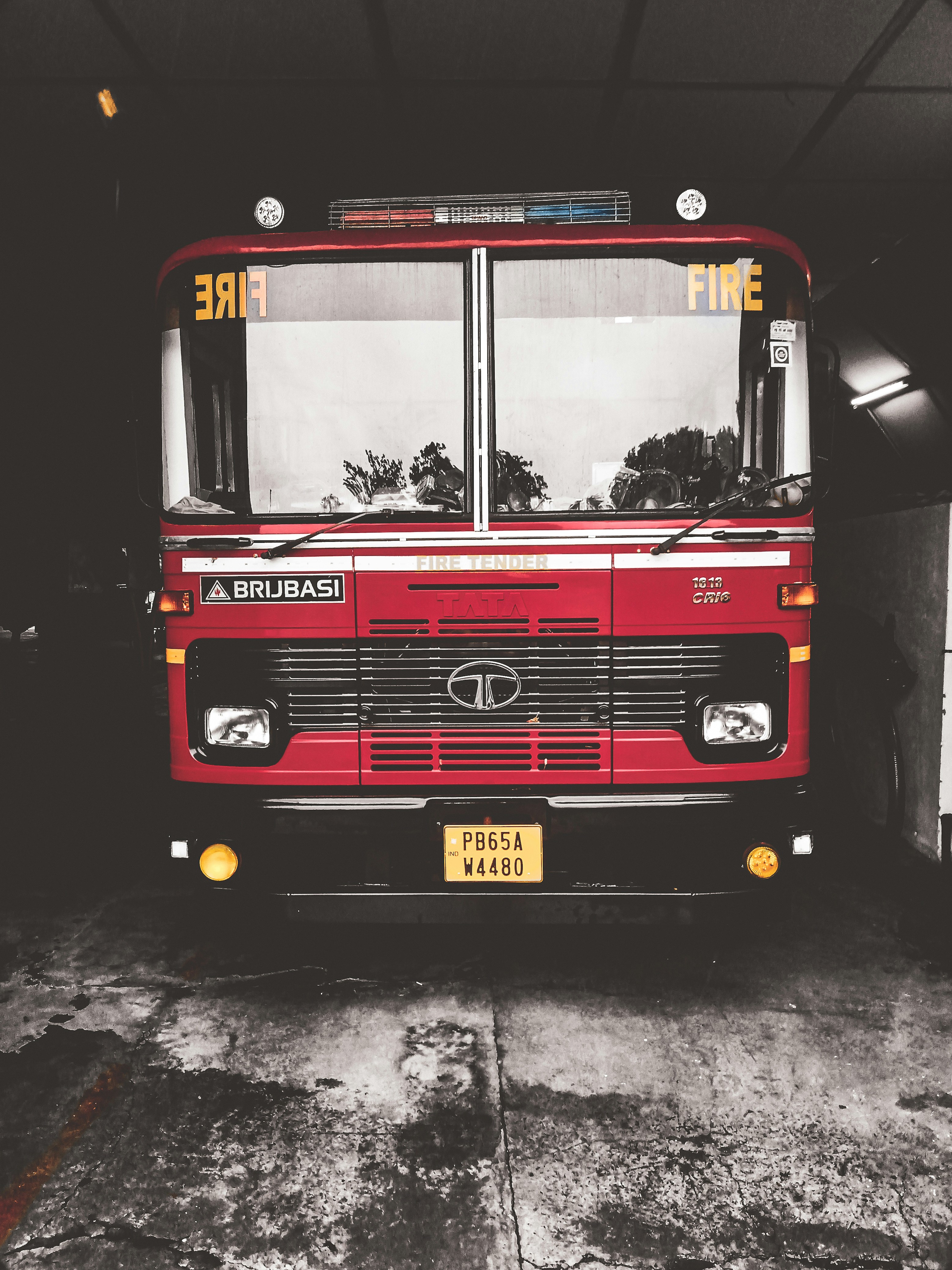 A vintage red fire truck parked in a garage, showcasing its bold lettering and distinctive features. The truck is partially illuminated, highlighting its classic design.