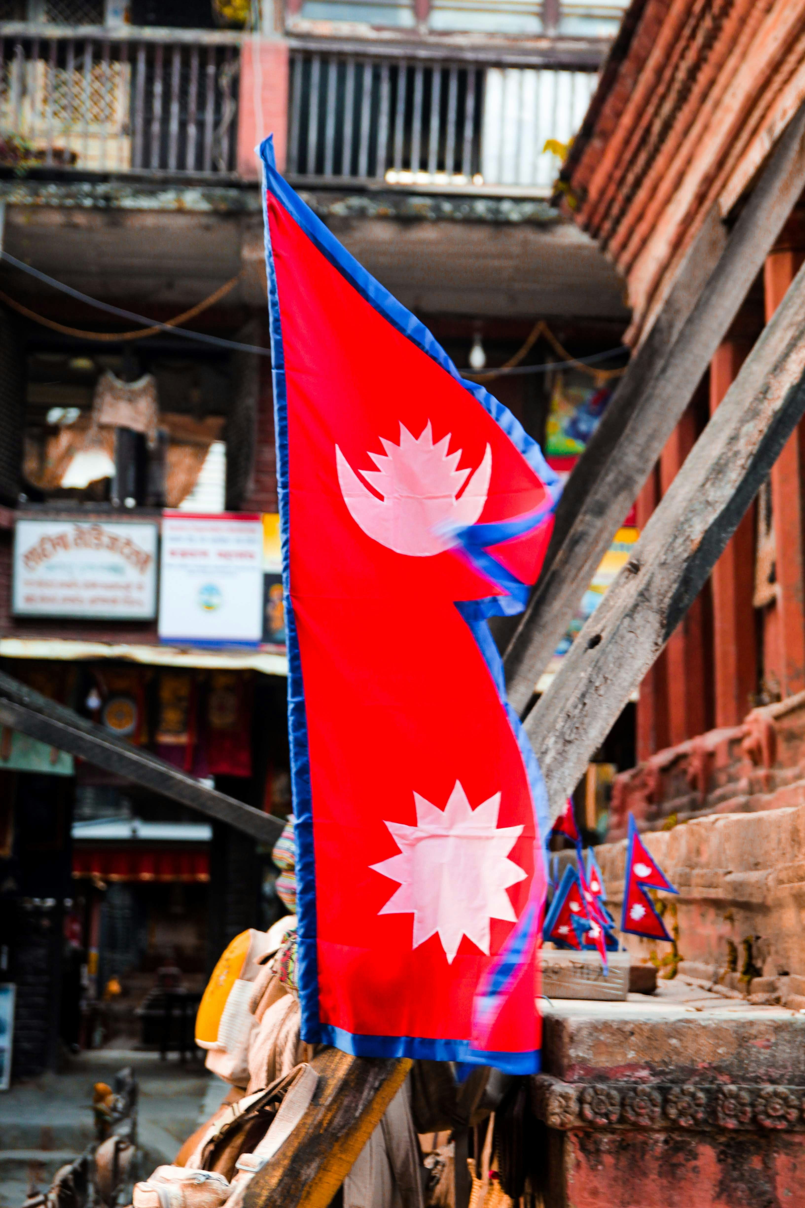 Vibrant Nepali flag fluttering amidst traditional architecture, symbolizing national pride and cultural heritage.