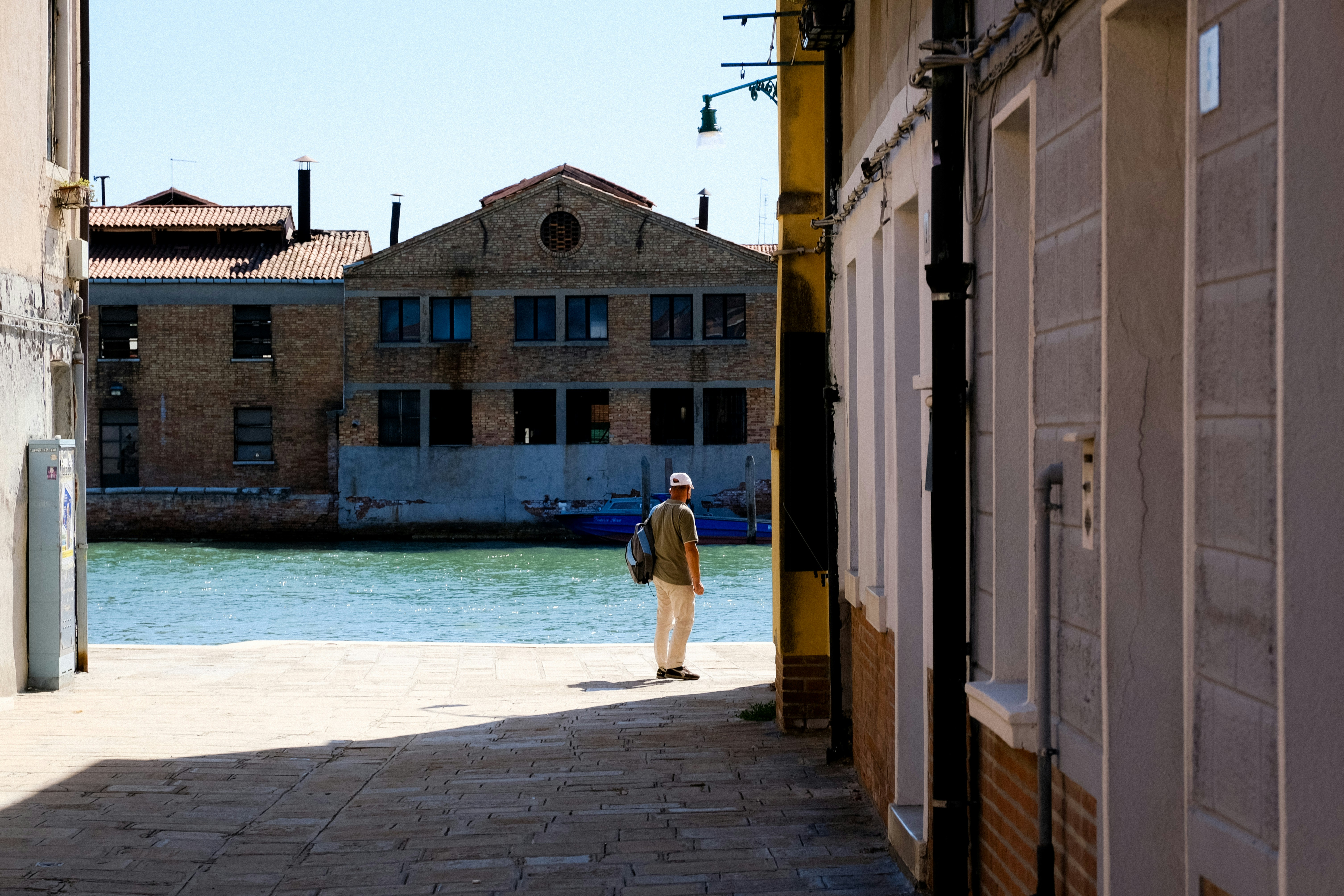 A man walking on a stone path between buildings photo – Free Building ...