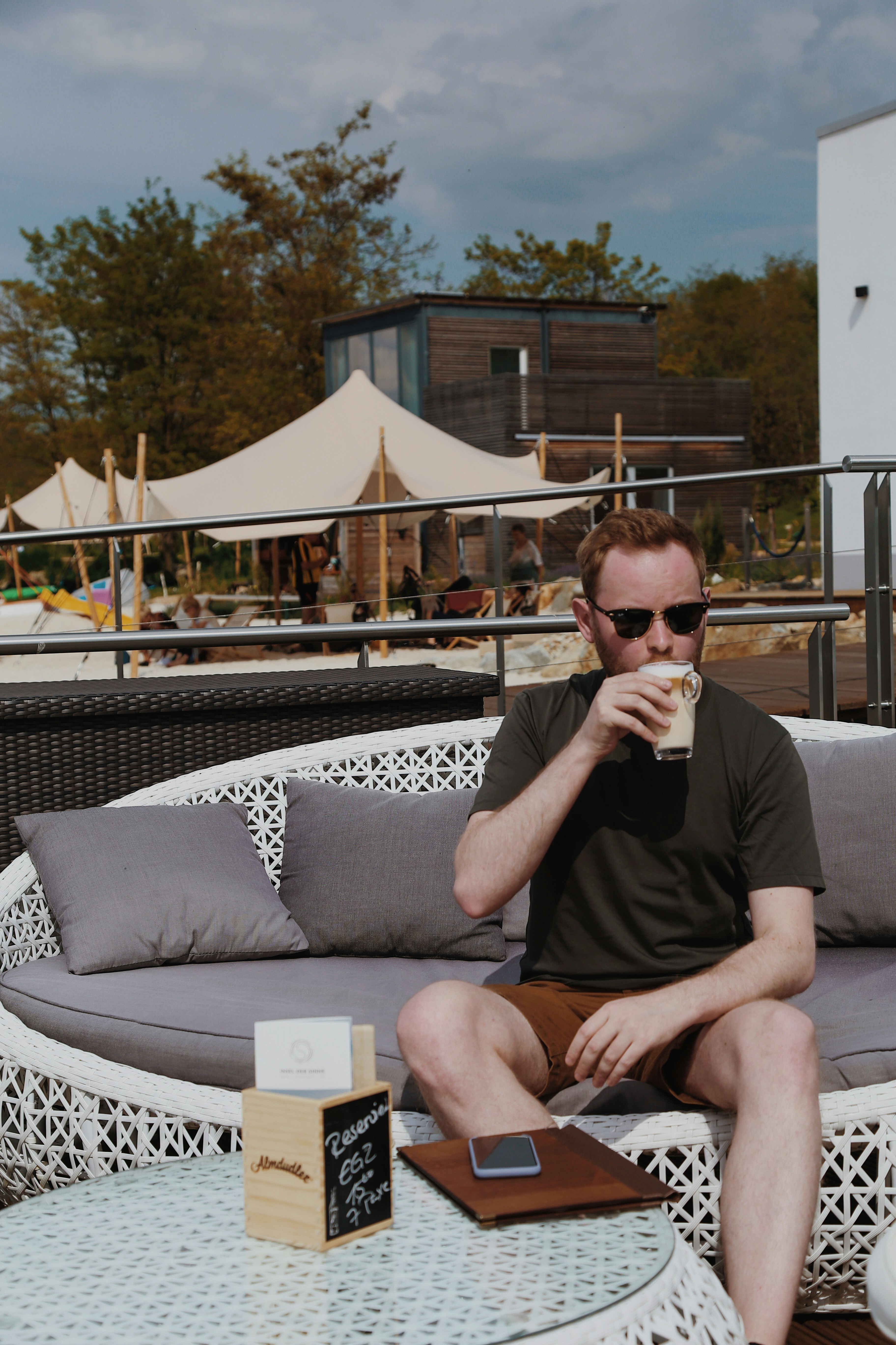 Patio Pause: A man enjoys coffee on a woven lounge in an outdoor lounge setting