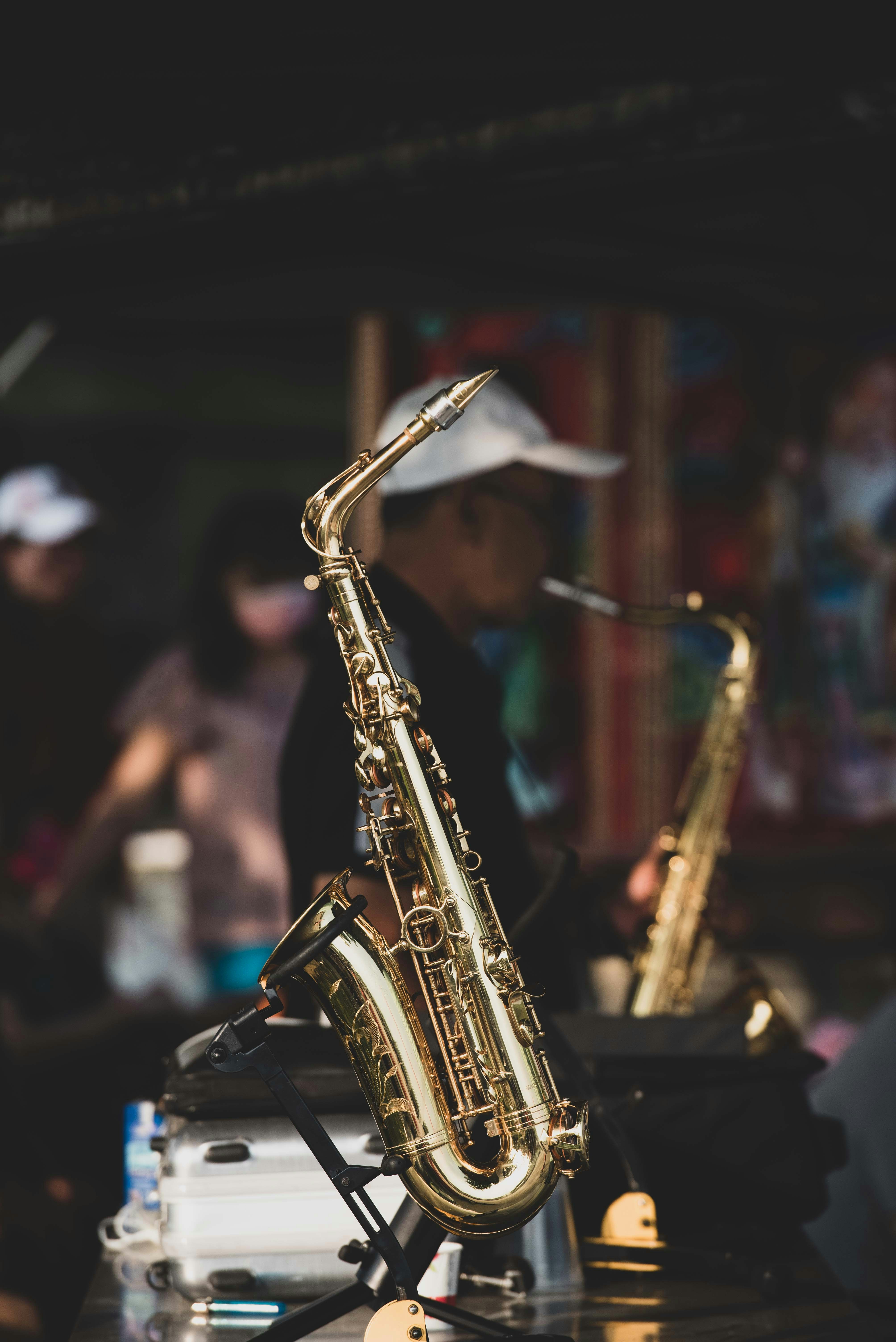Two saxophones poised in a lively outdoor performance, capturing the essence of music and community. The blurred background hints at an engaged audience.