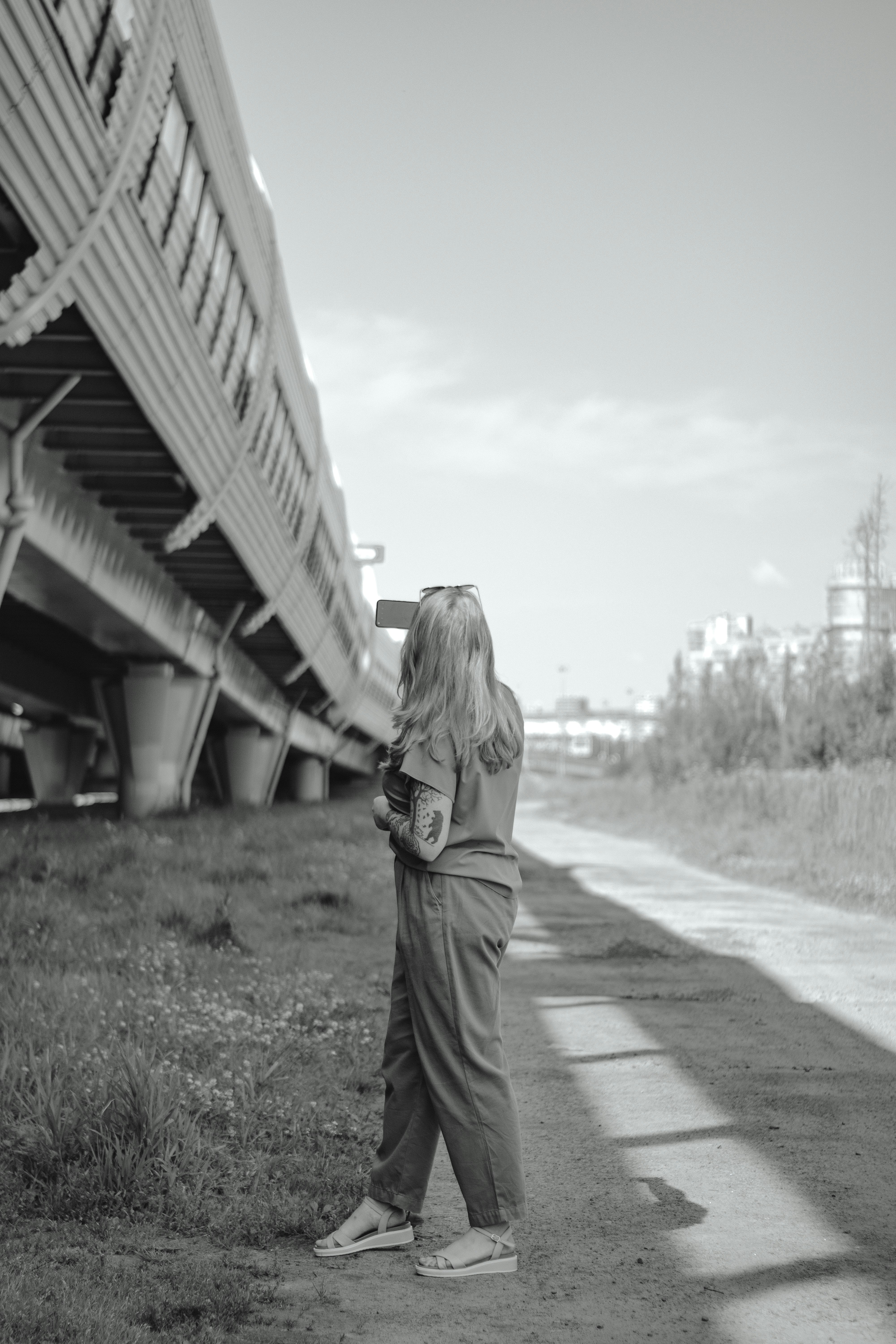 Portrait on a Gravel Path Under the Looming Industrial Bridge