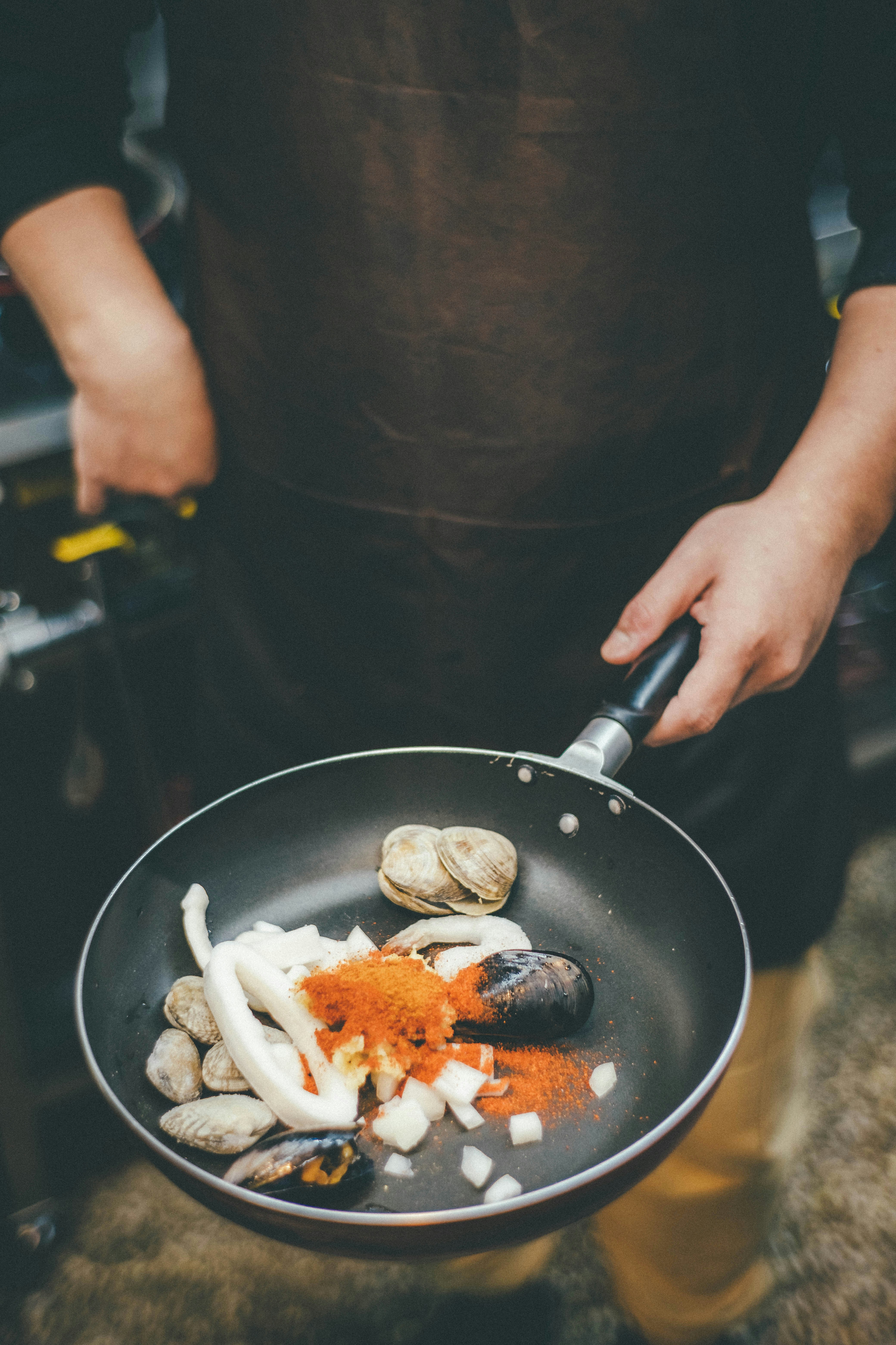 A person cooking food in a pan photo – Free Seashell Image on Unsplash