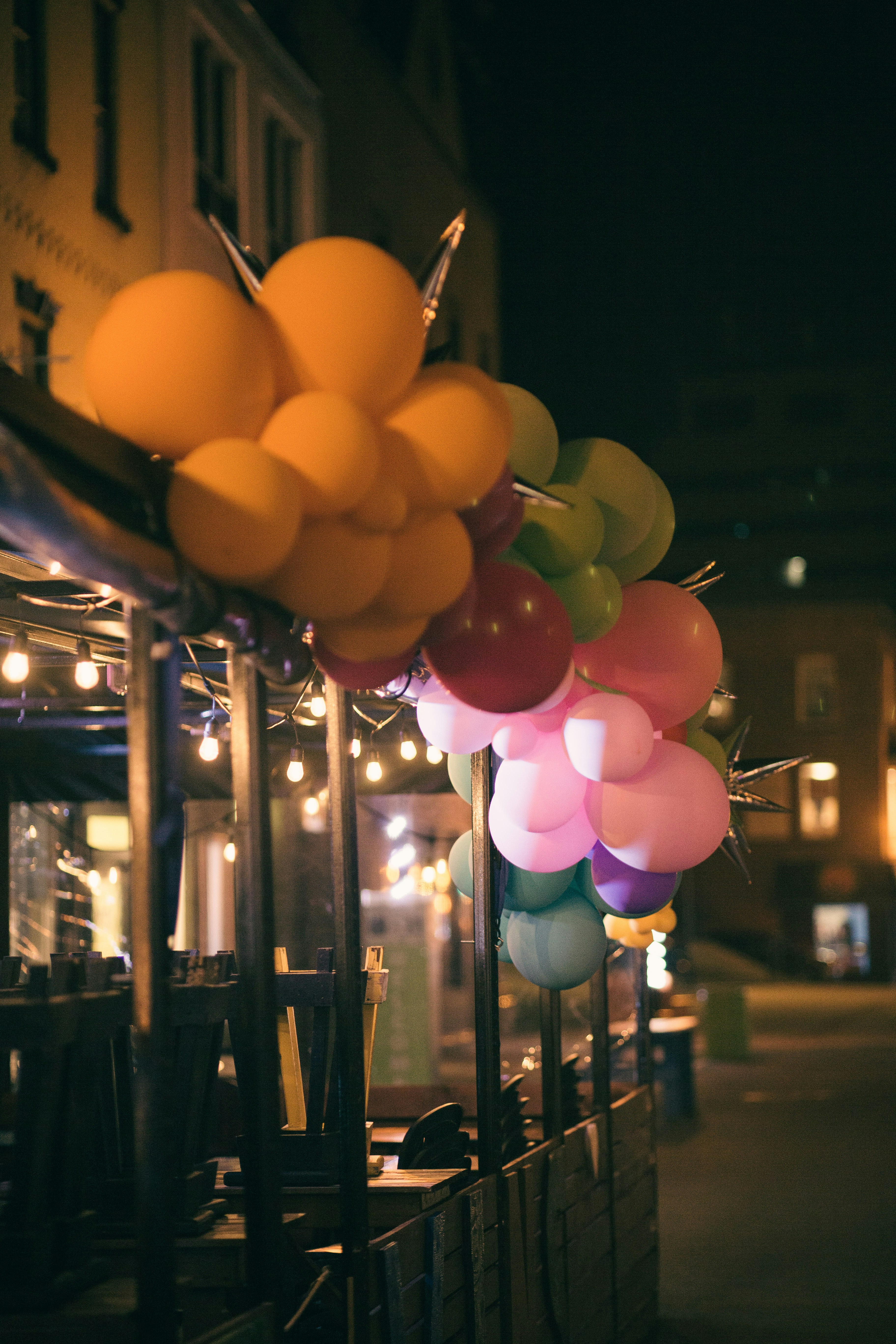 Colorful Balloon Cascade Along a Night Market Terrace