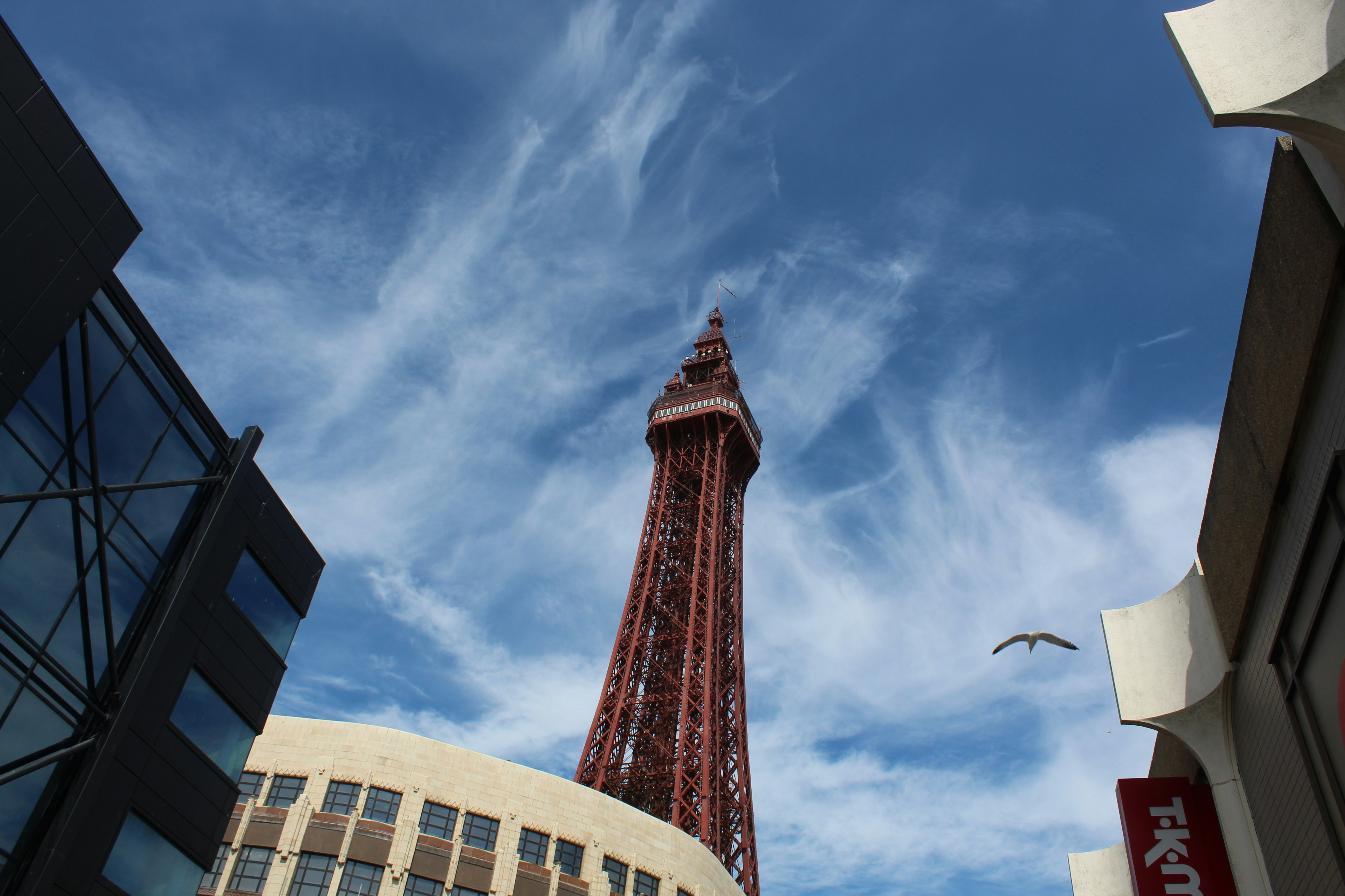 Crimson Lattice Tower Rises Over a Glass-Fronted City