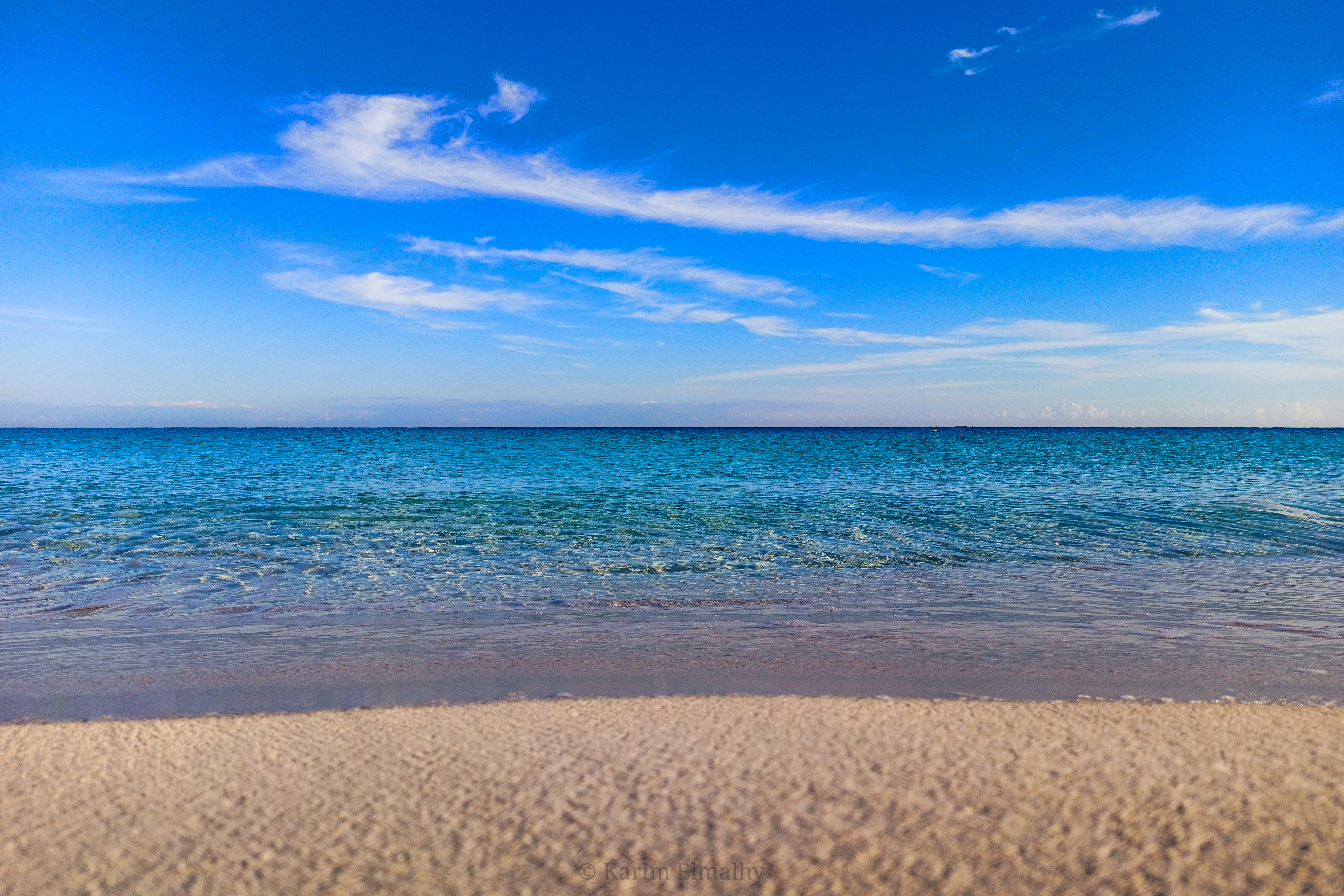 Gentle waves lapping at a sandy beach under a clear blue sky, evoking a sense of peace and relaxation.