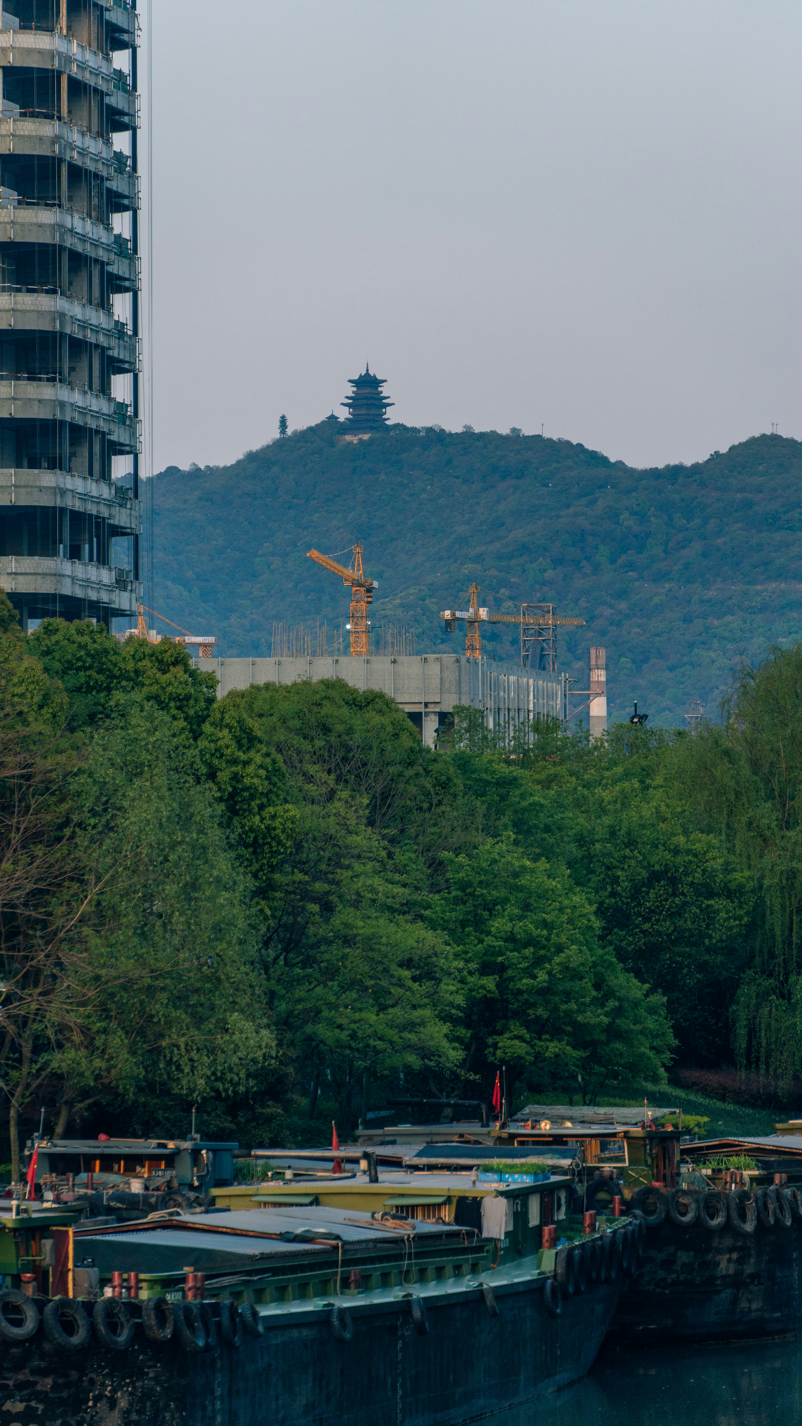 a large building next to a body of water with trees and a hill in the background