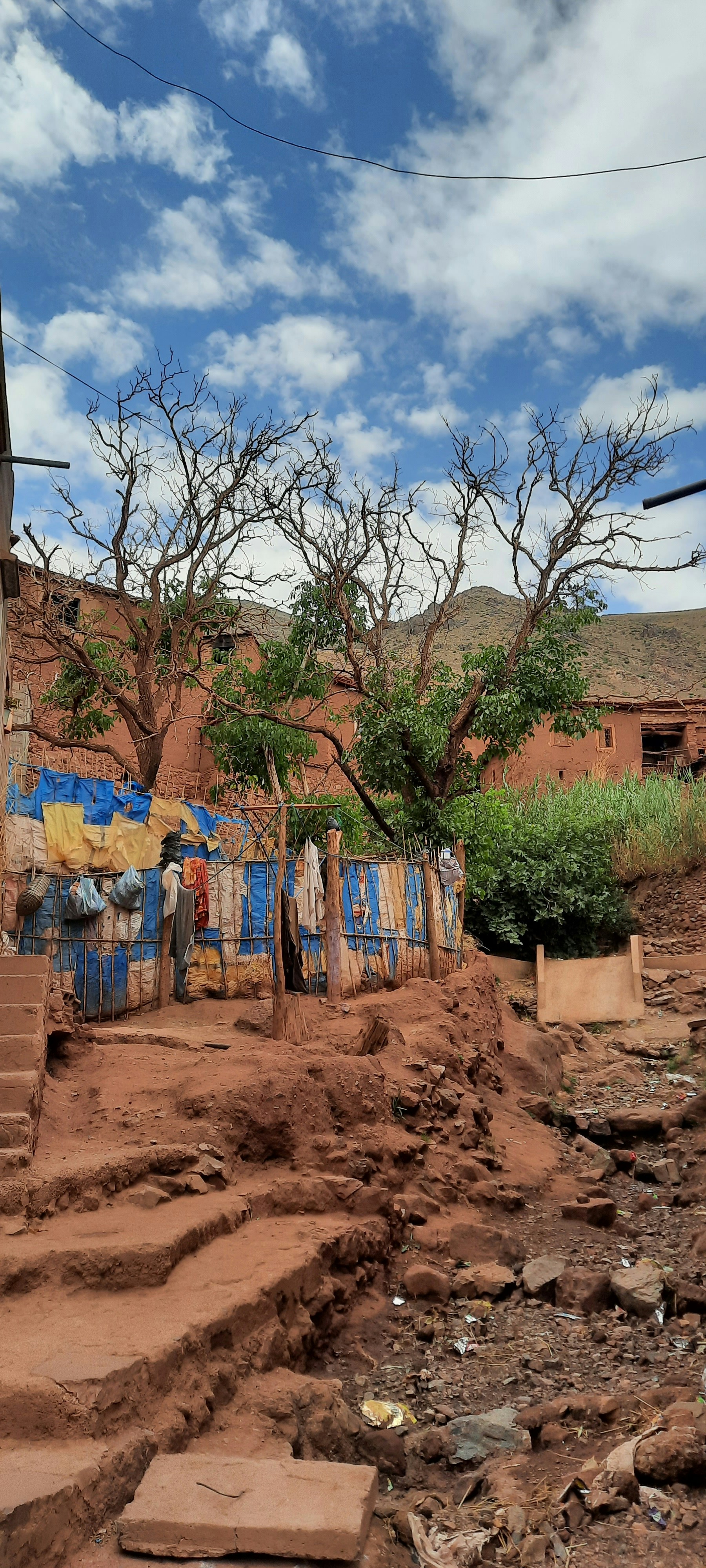 Blue-Tarp Border Across a Sunbaked Clay Village