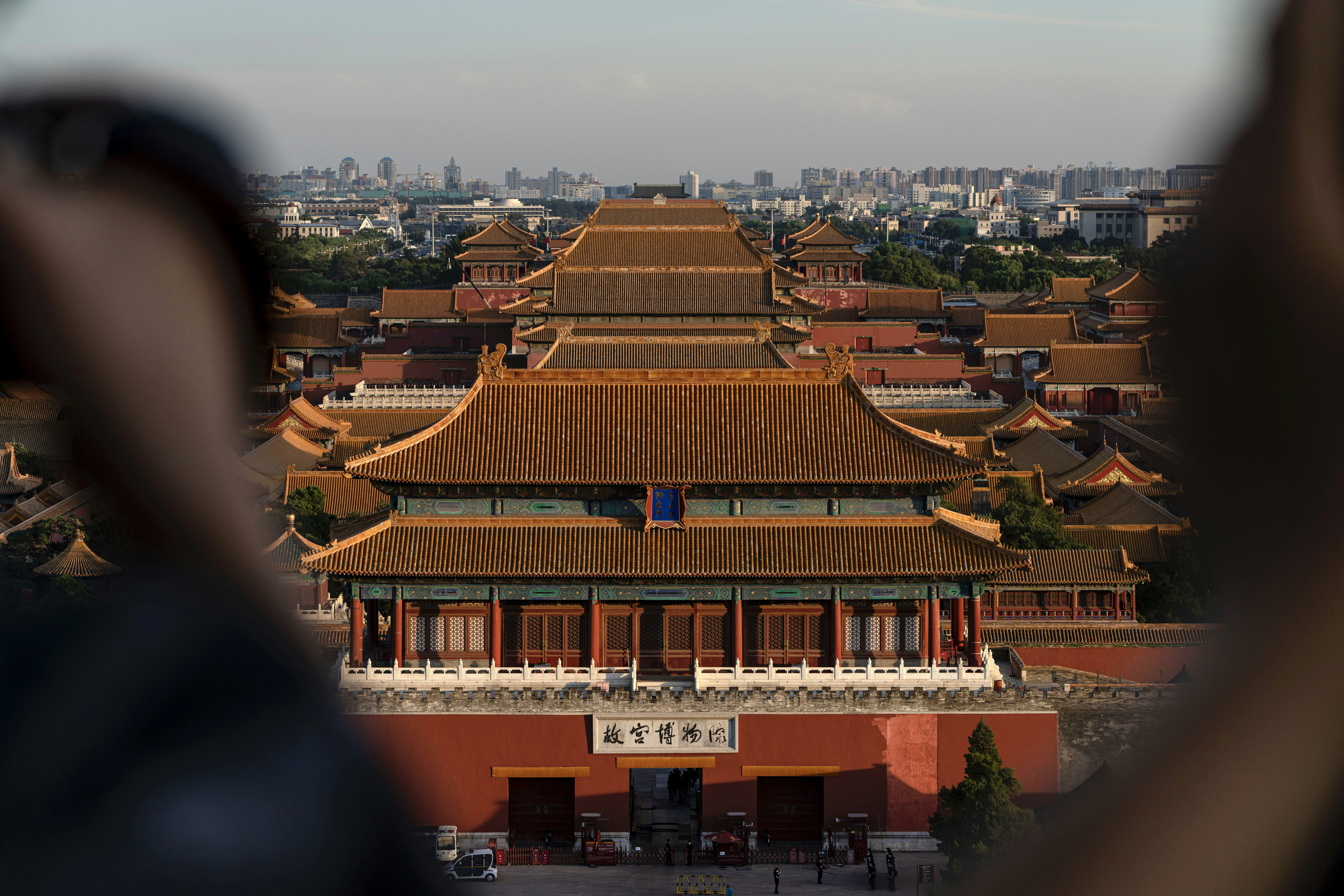 View of the Forbidden City showcasing its iconic golden rooftops and traditional architecture against a modern skyline backdrop.
