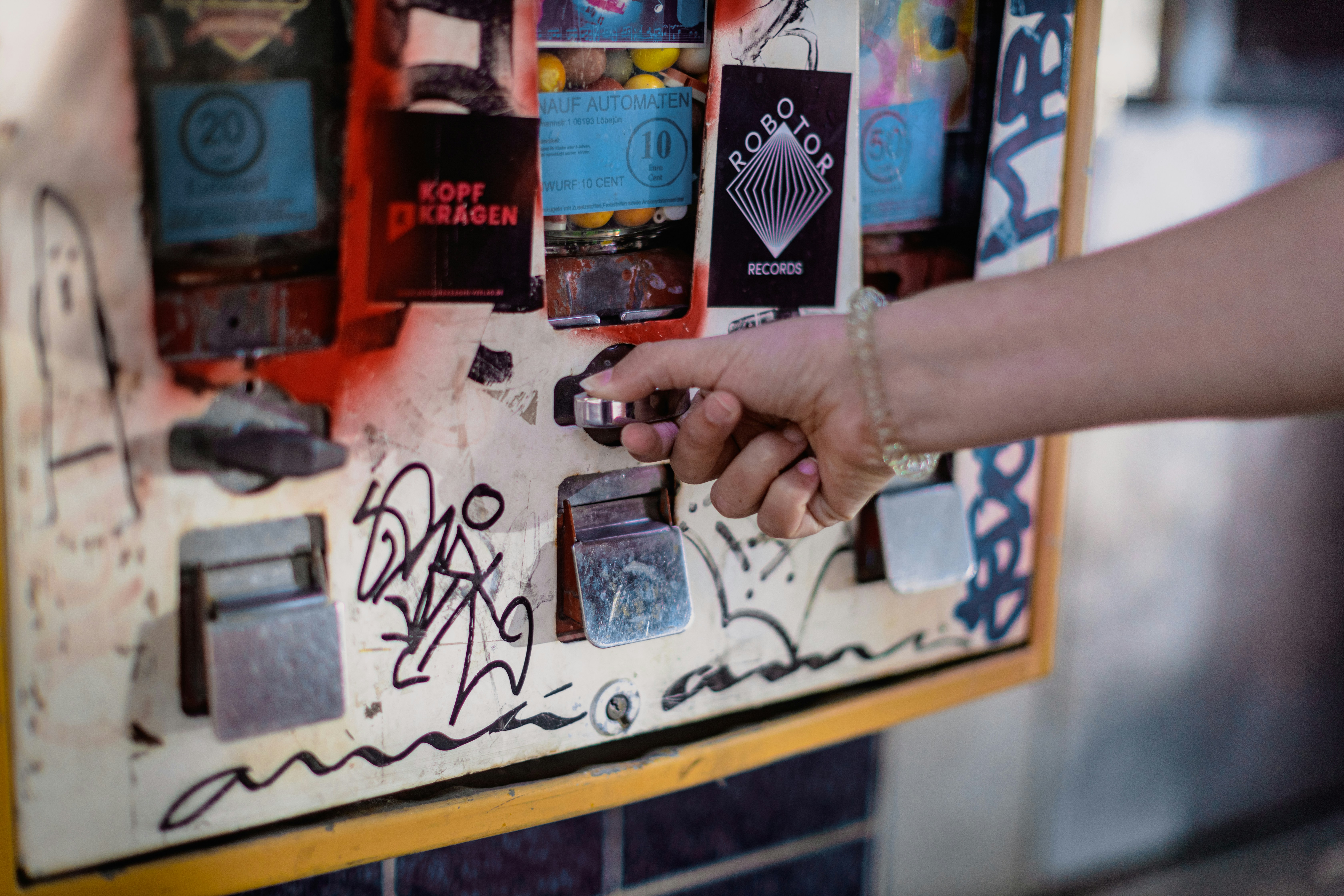 Pressed Coin of Graffiti and Gears: A Close-Up on the Hand Engaging a Locked Vending Panel