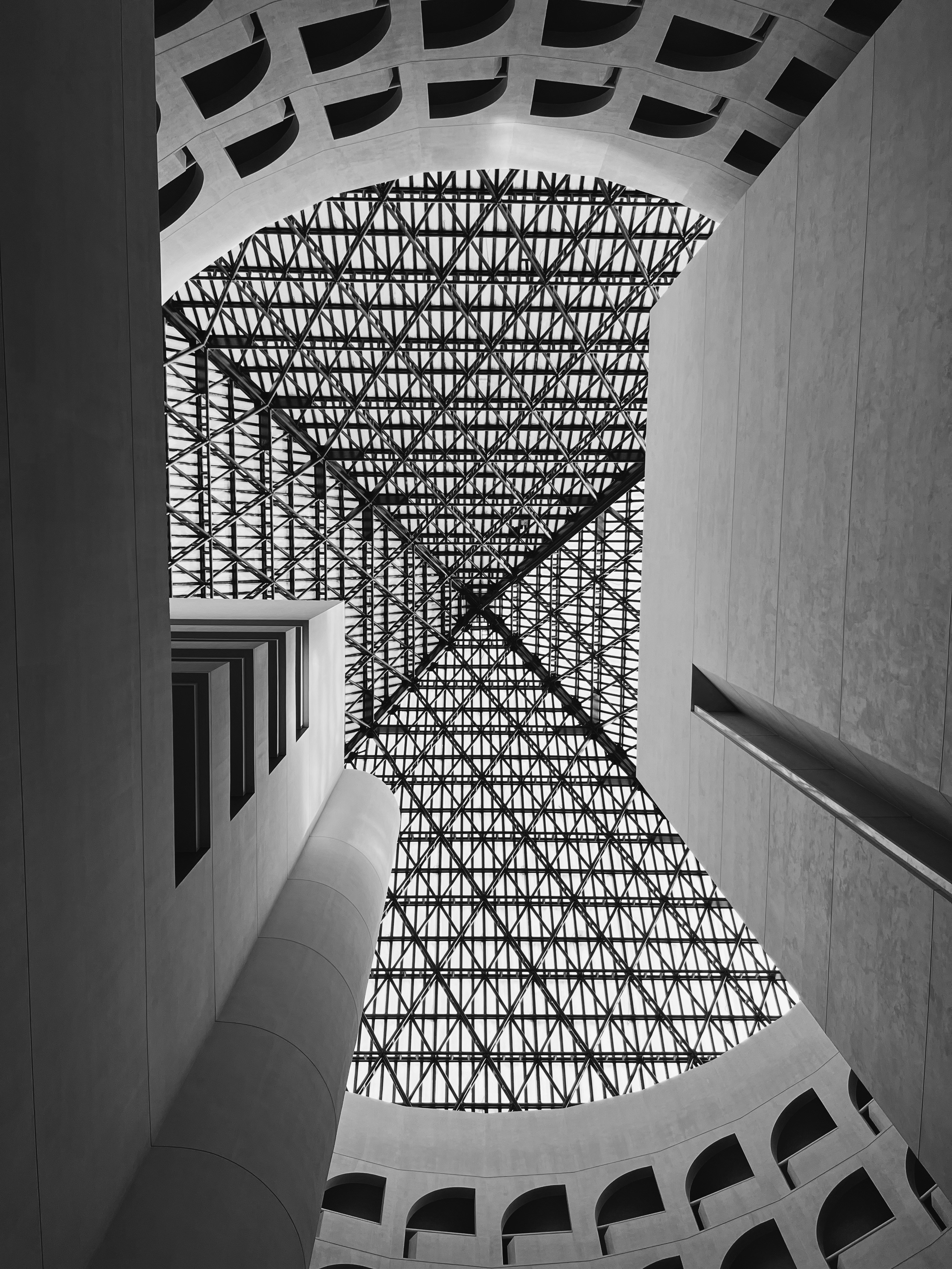 Converging Lattice: Grayscale Glass Dome Above a Concrete Atrium