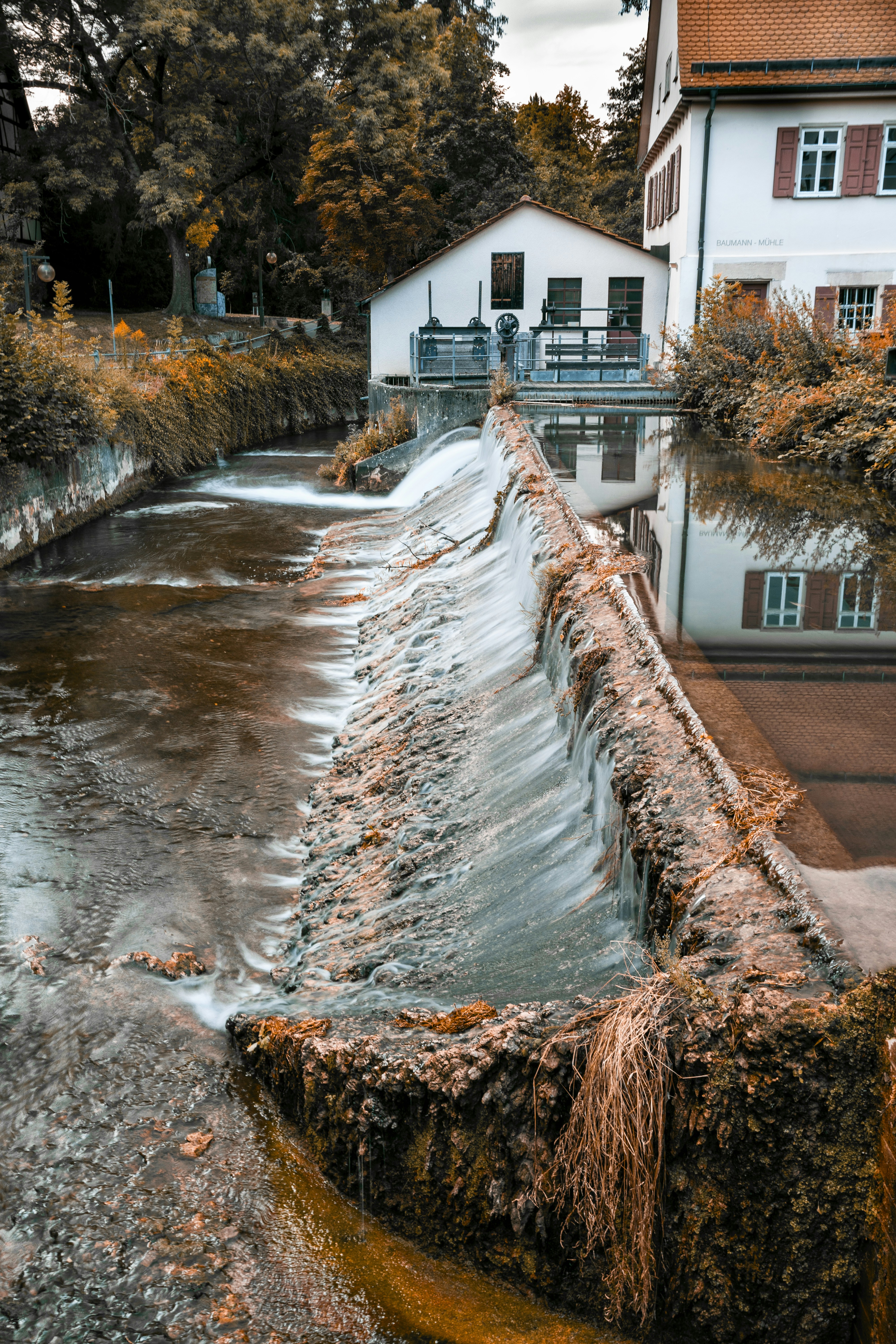 Riverside Weir: Autumn Cascade Between a Quiet House and Reflections