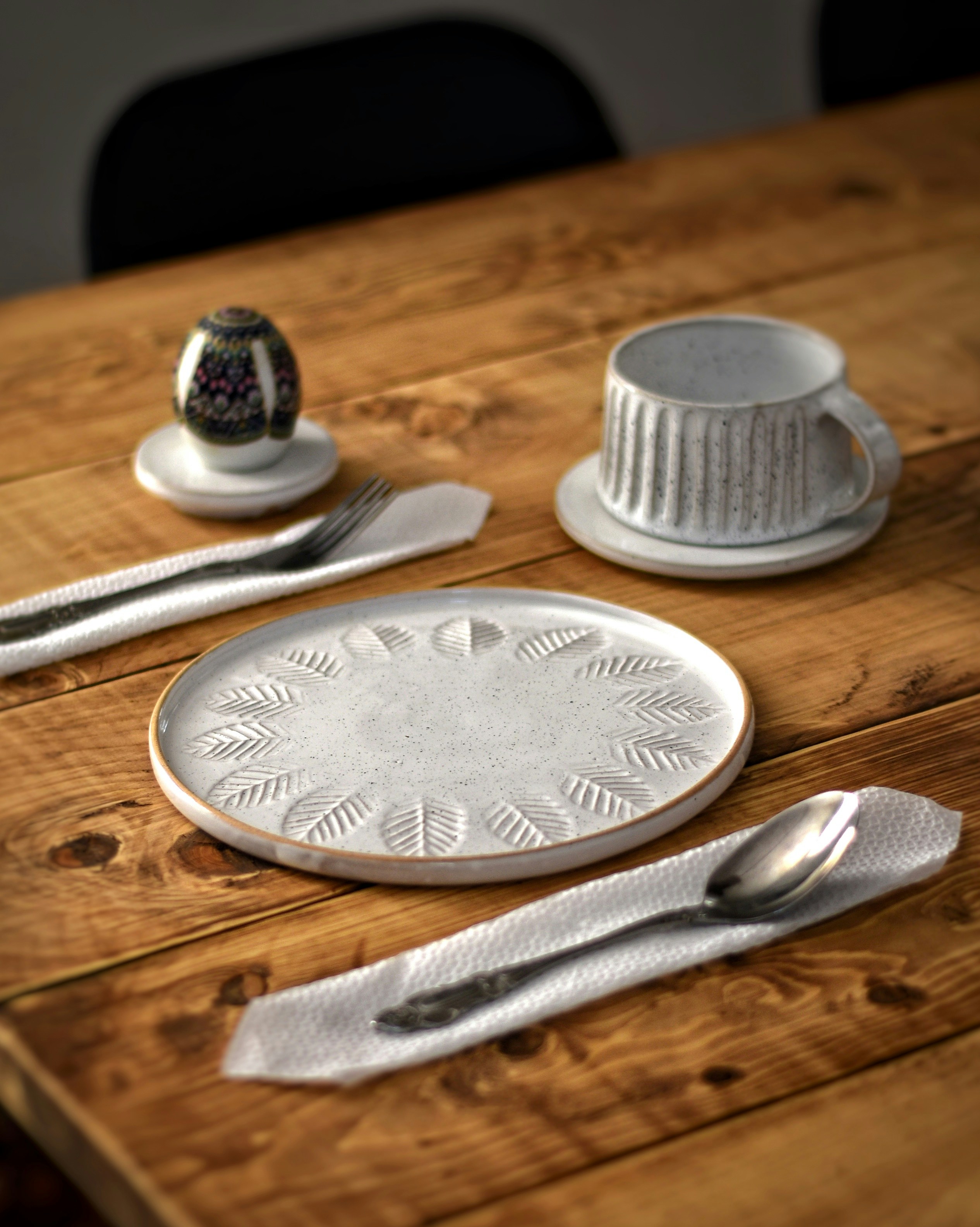 Leaf-Pattern Plate on a Warm Wooden Table Framed by a Mug and Petite Ornamental Egg