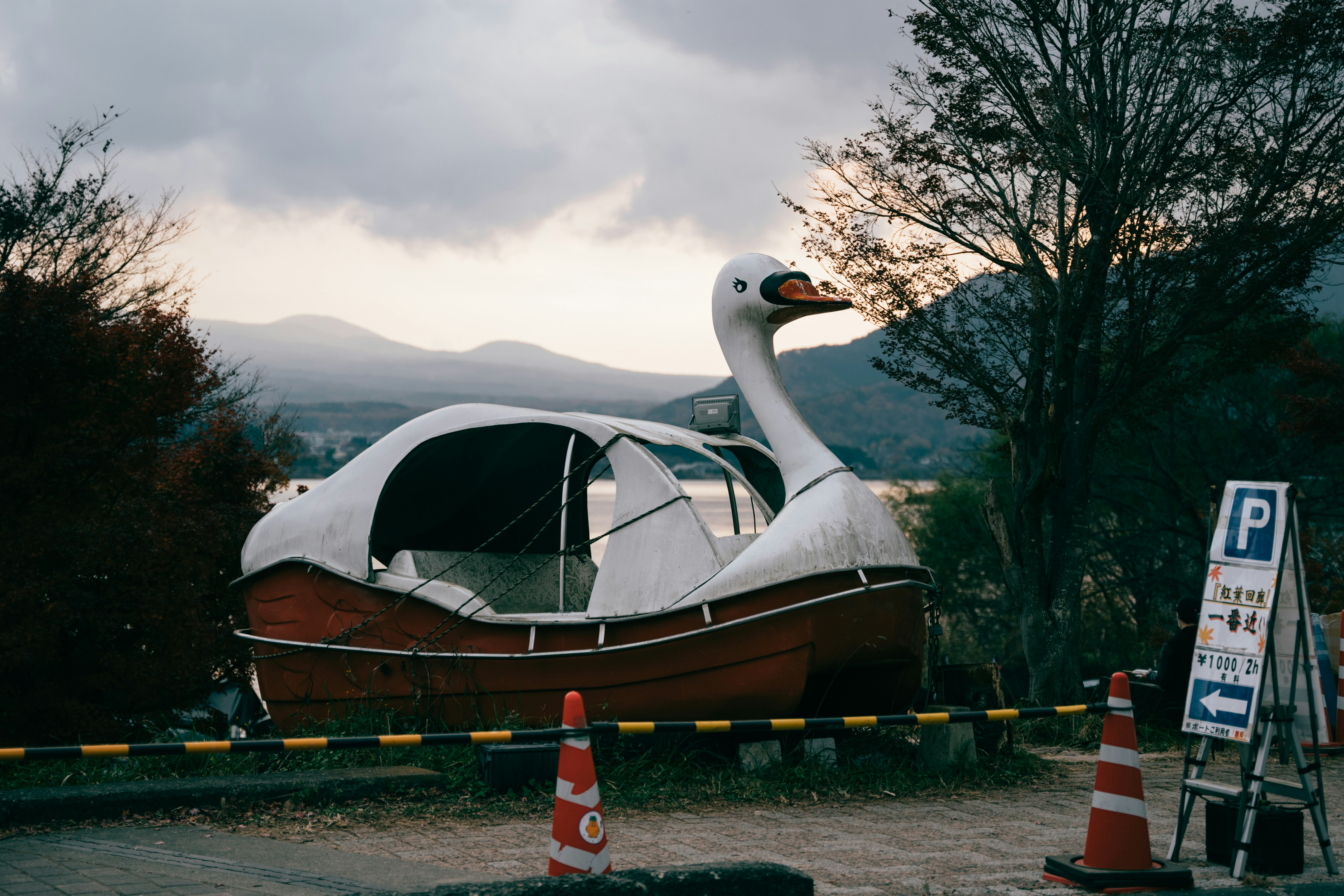 Swan-Boat in a Parking Lot: Quiet Drama Against a Mountain Backdrop