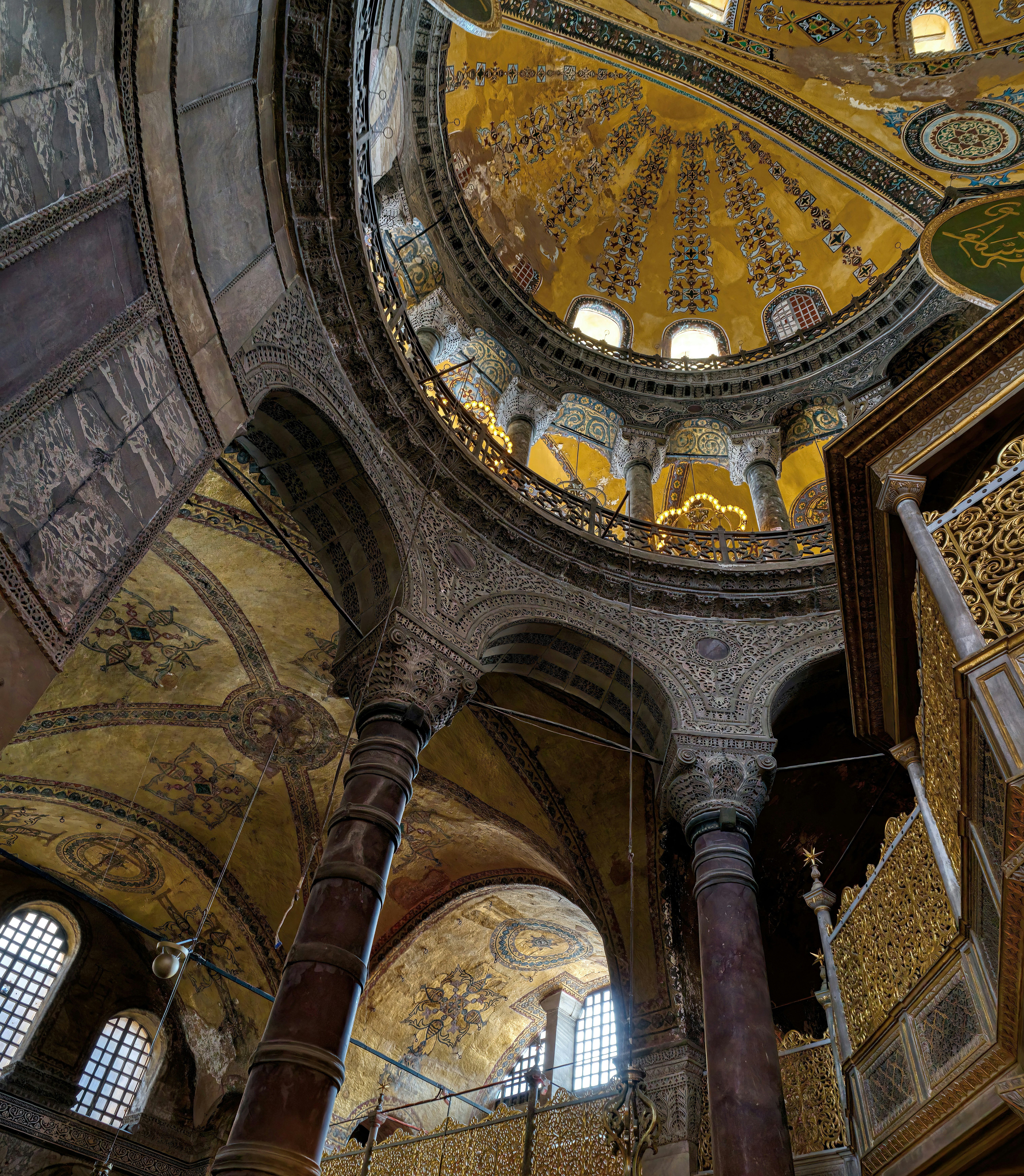 Ornate domed ceiling with intricate mosaics and arched windows in a historic structure.