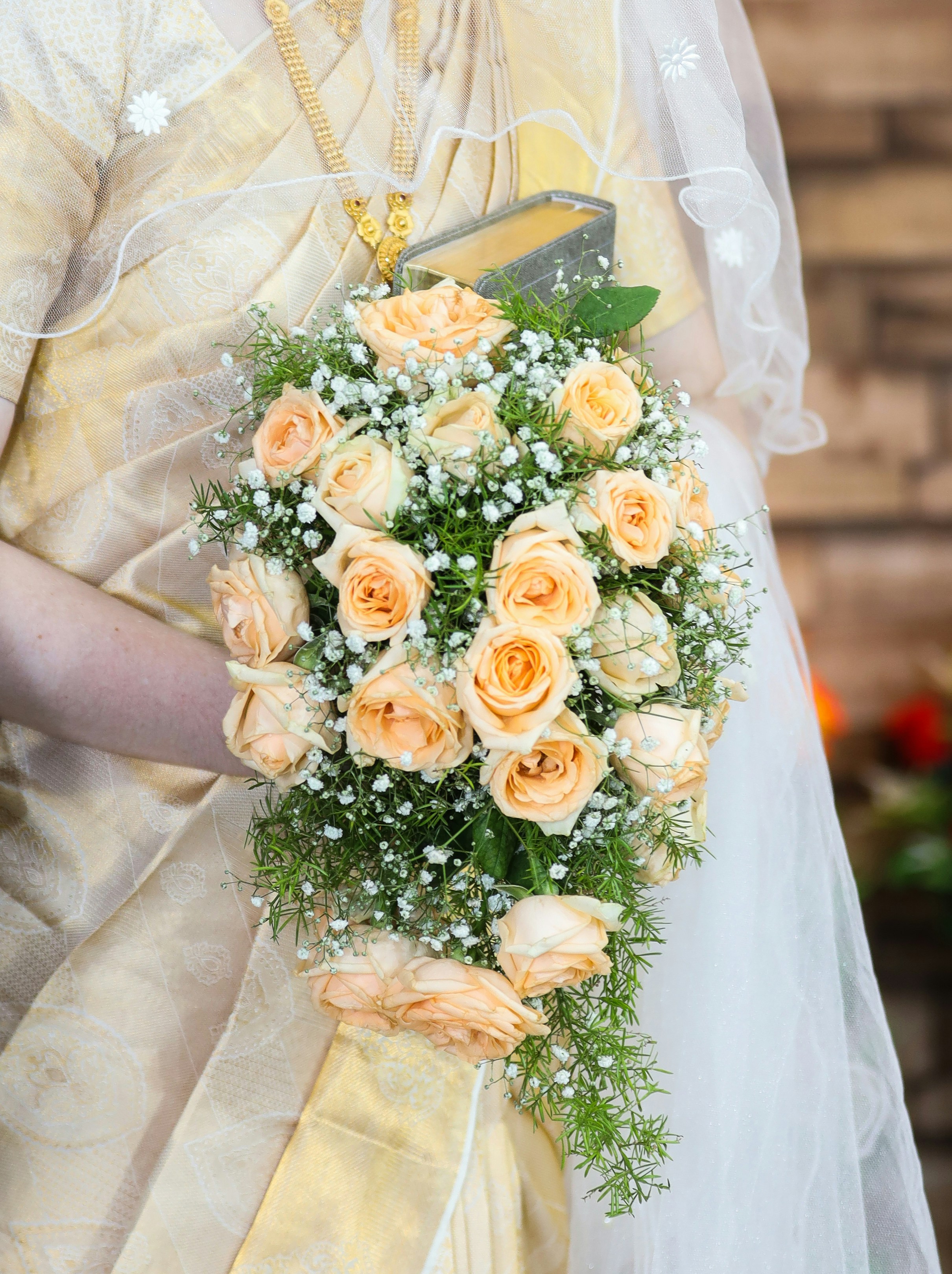 Bride holding a cascading bouquet of peach roses and baby's breath.