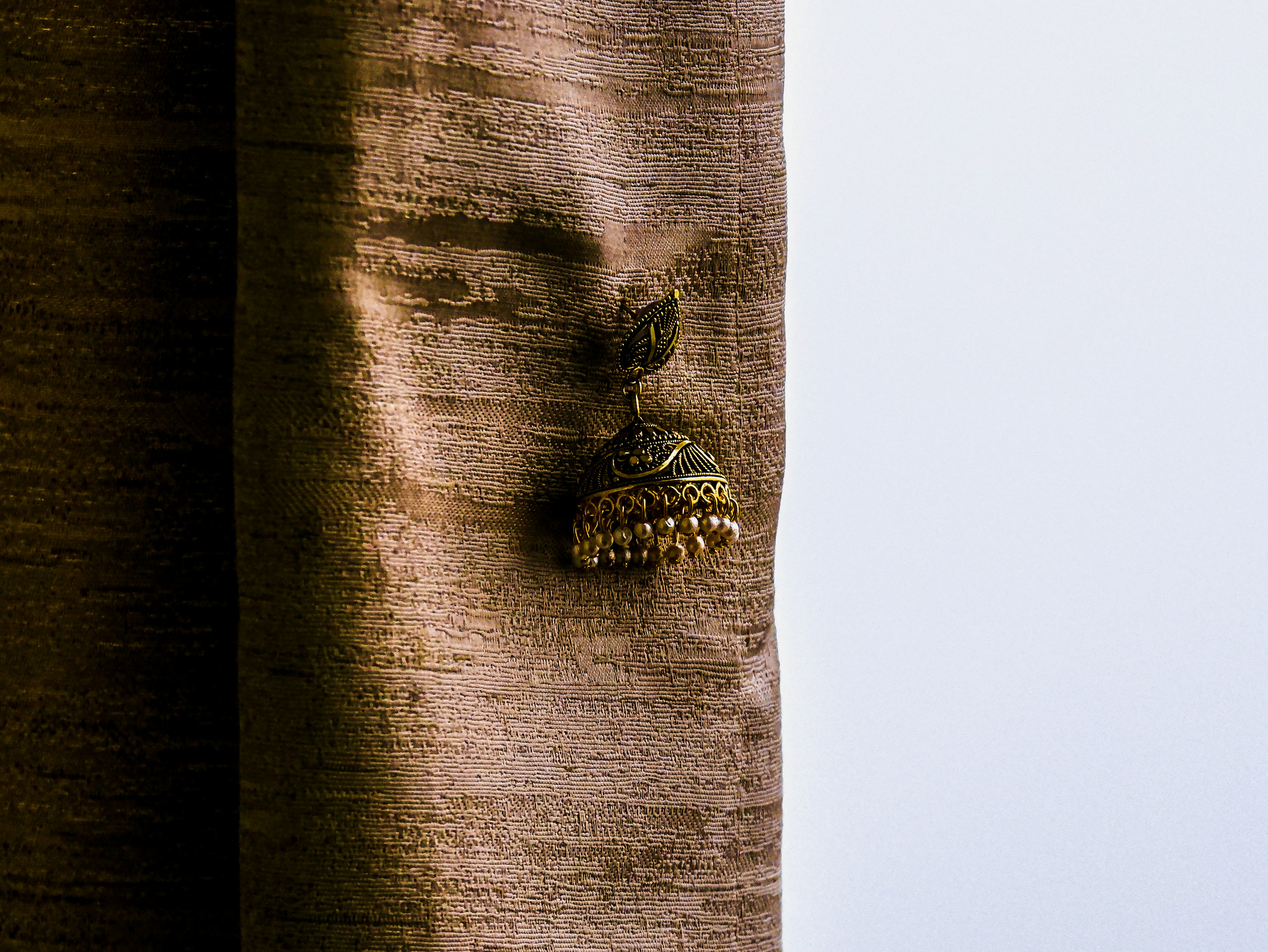 Brass Bell Clings to a Palm Trunk Against a Pale Sky