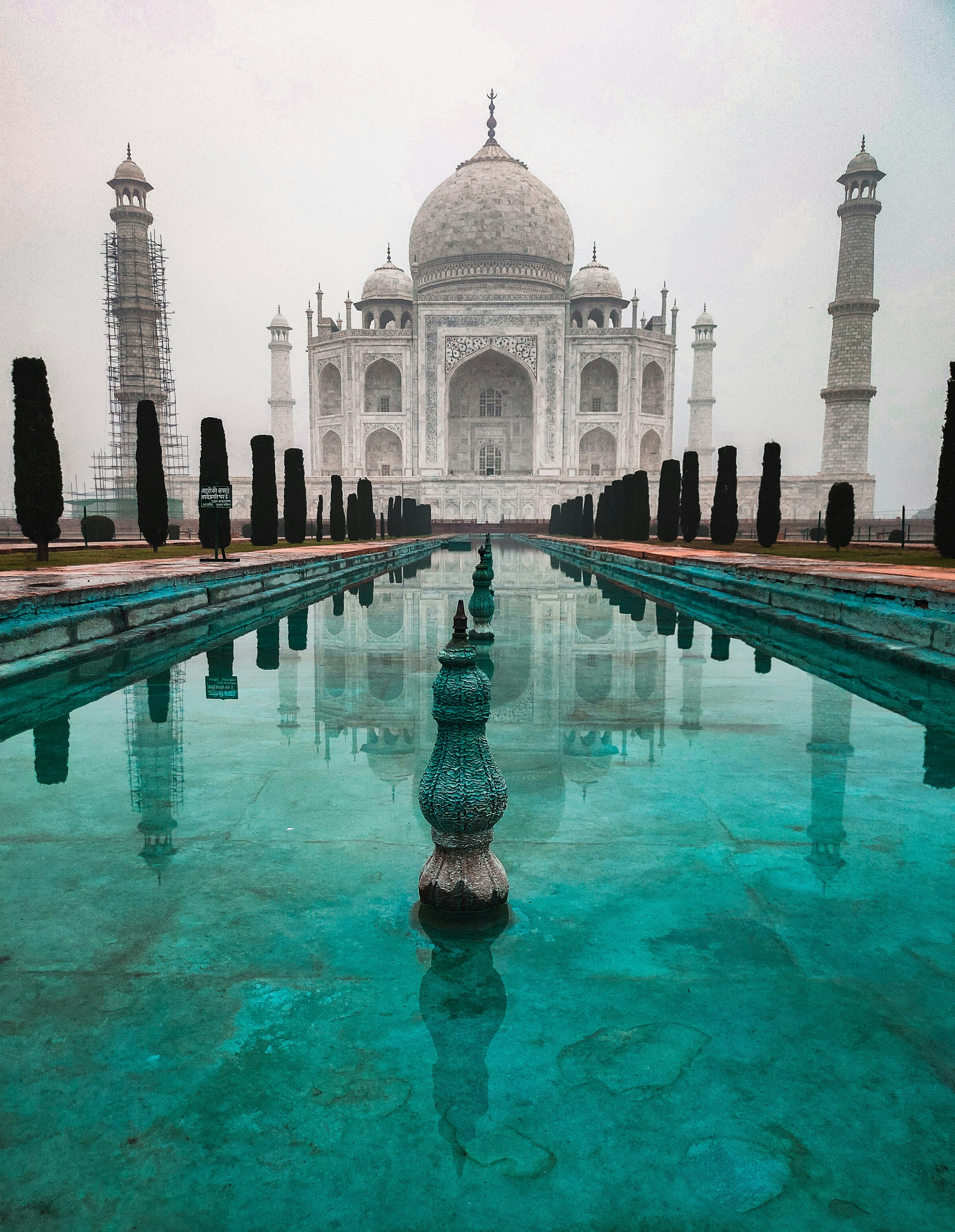 A large white building with towers with Taj Mahal in the background ...