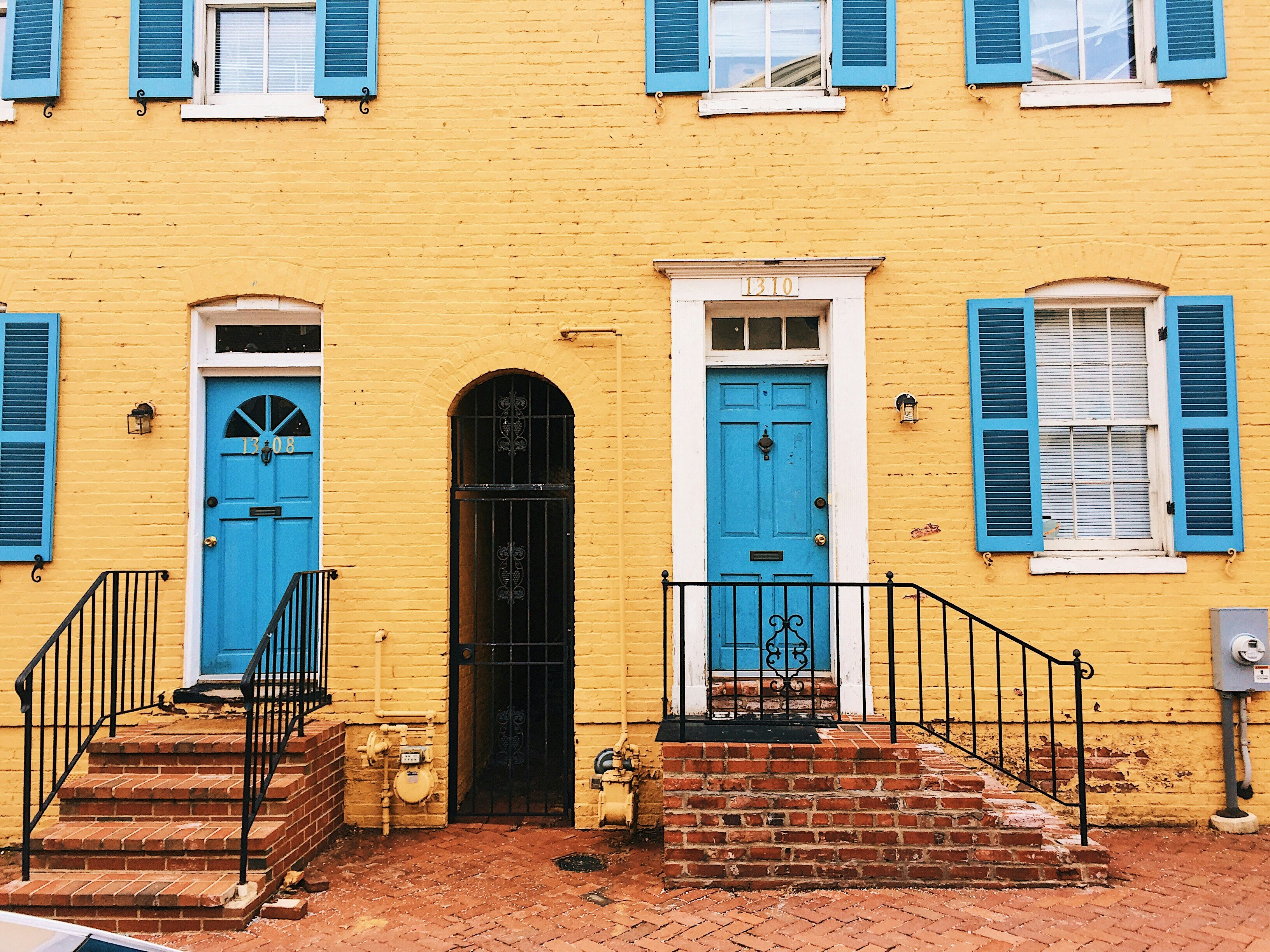Row of Bright Blue Doors on a Sunny Yellow Brick Facade