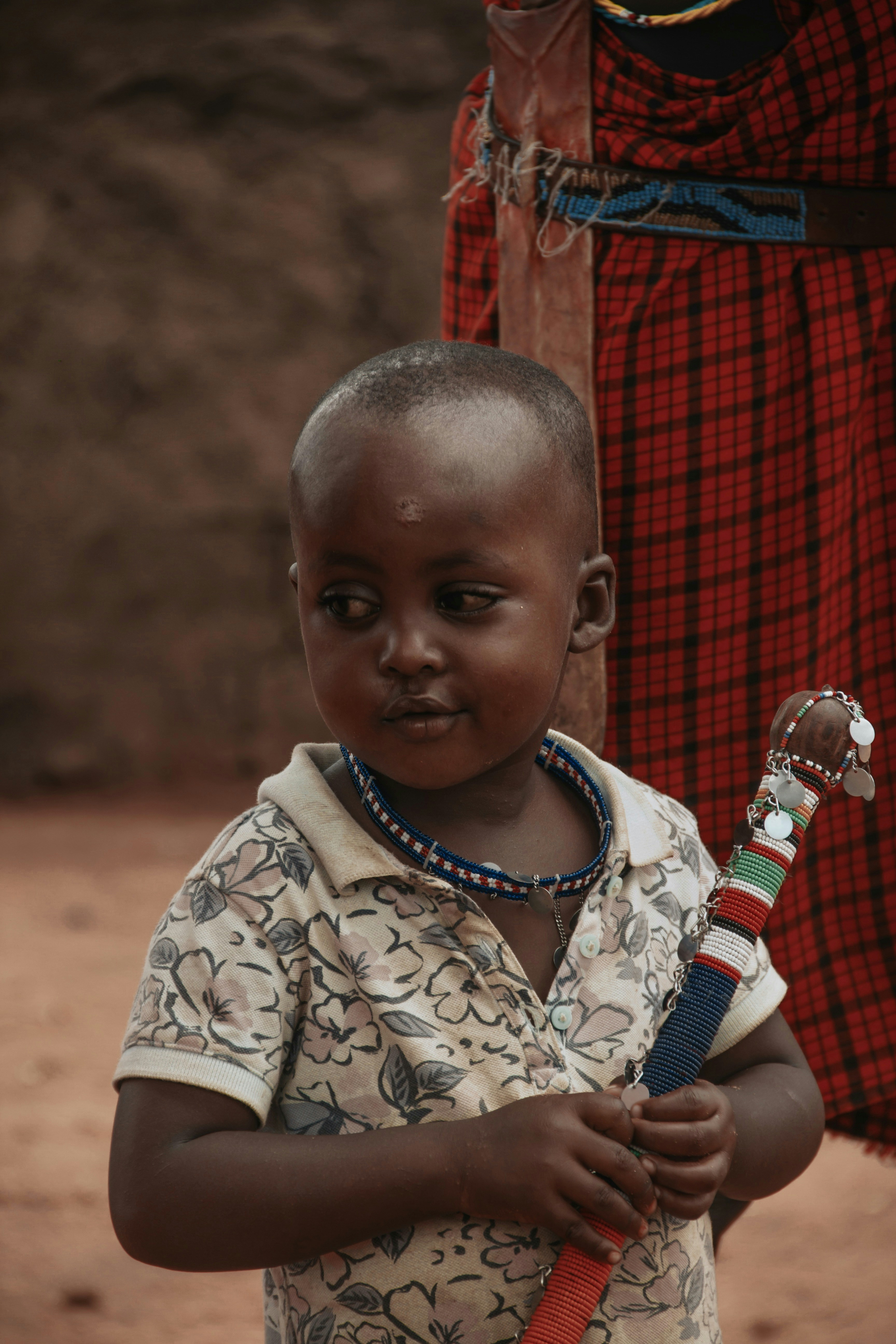 Young child holding a colorful staff, adorned in traditional attire, exuding a sense of innocence and cultural heritage.